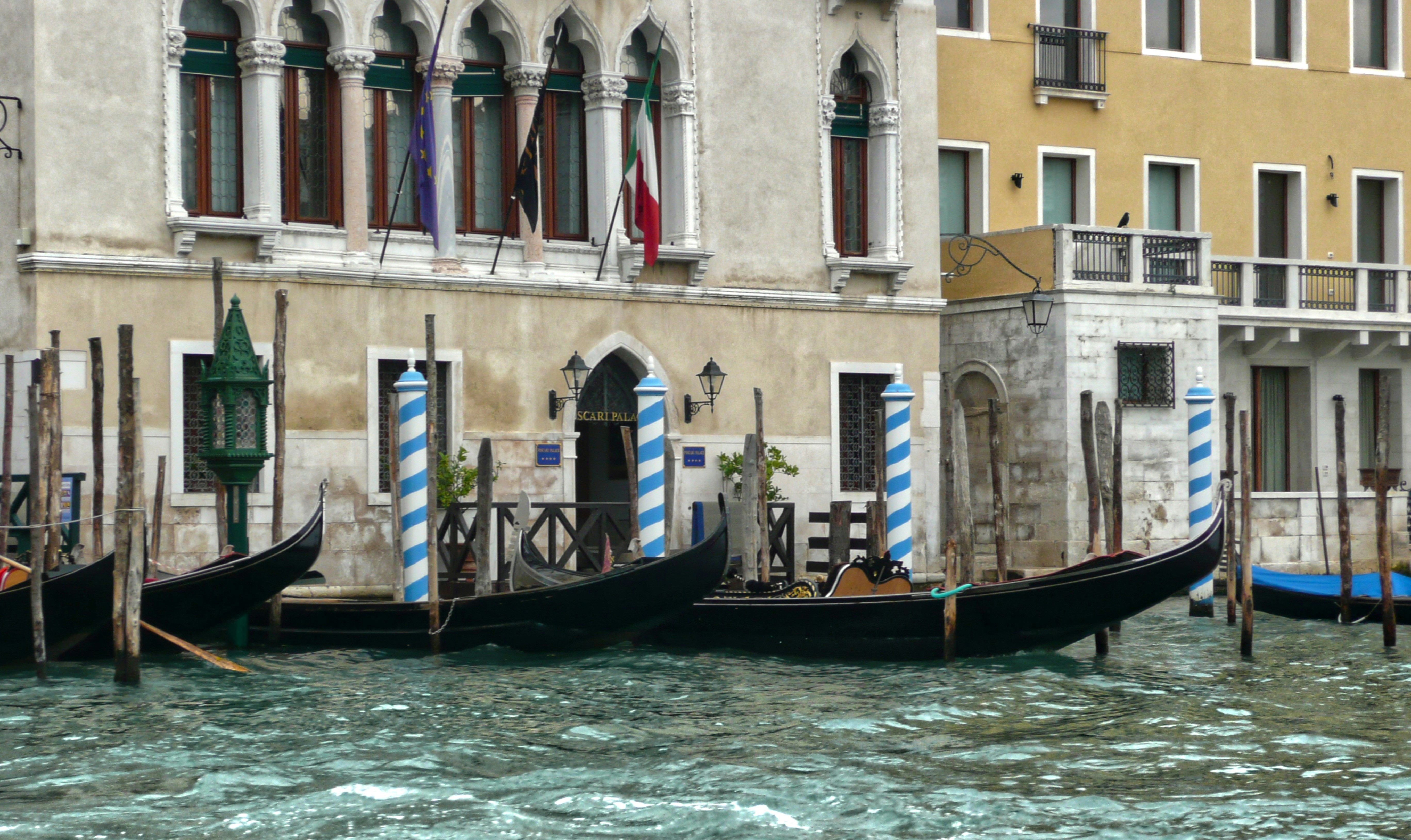 Gondolas moored along a canal beside a historic building in Venice, showcasing the unique architectural style and vibrant colors of the city.