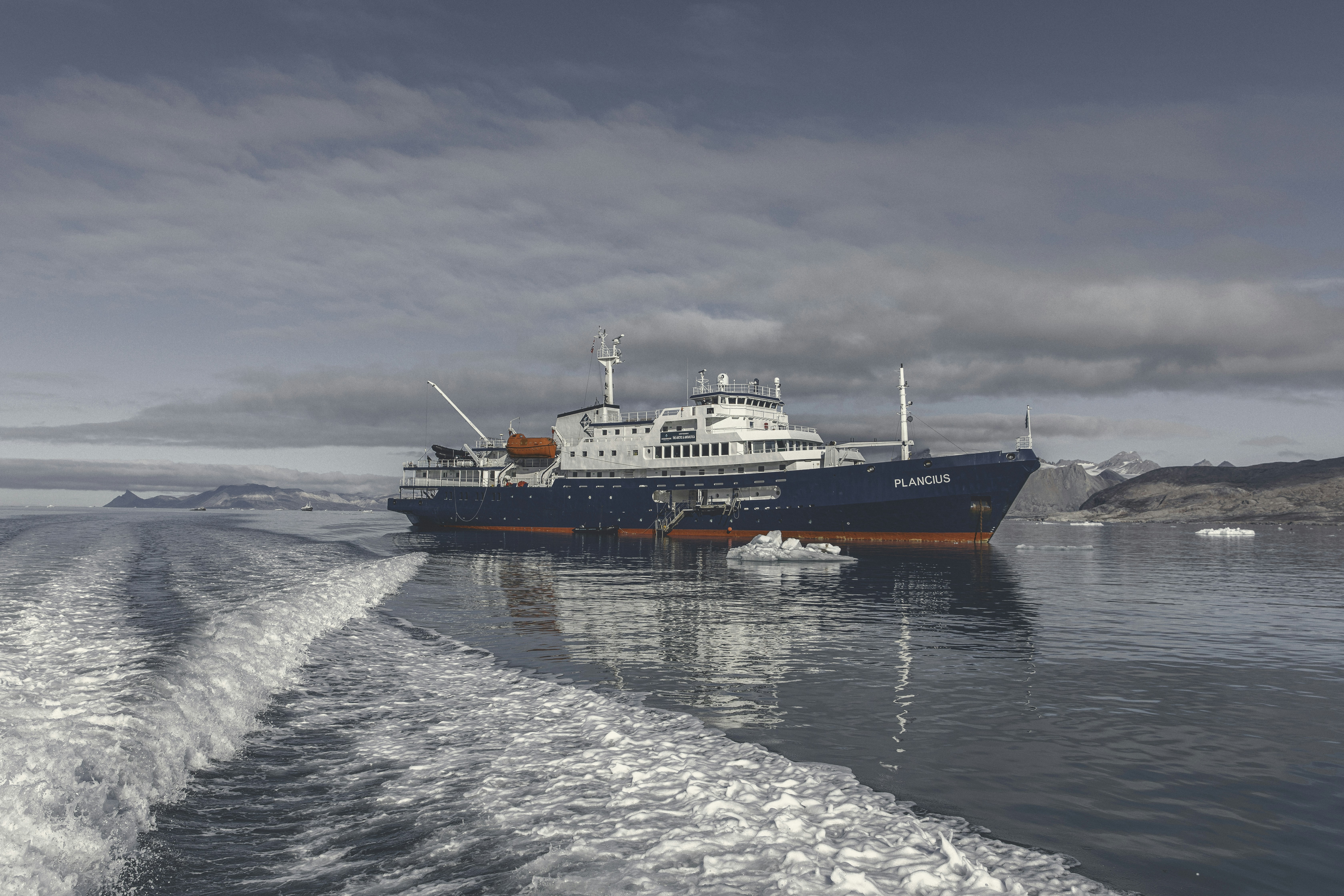 Red and white ship on sea under white clouds during daytime photo ...