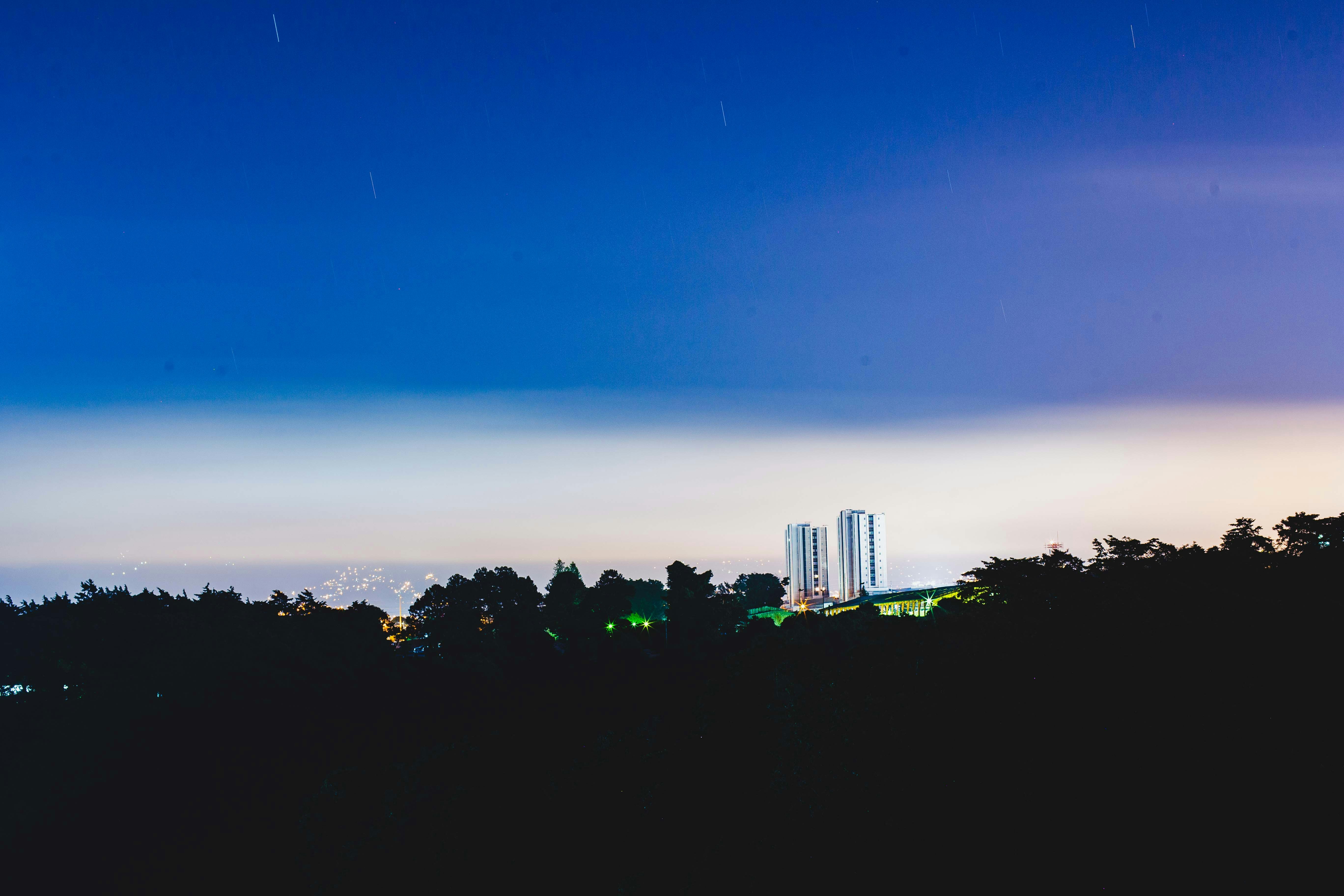 City skyline silhouetted against a gradient twilight sky with visible stars.