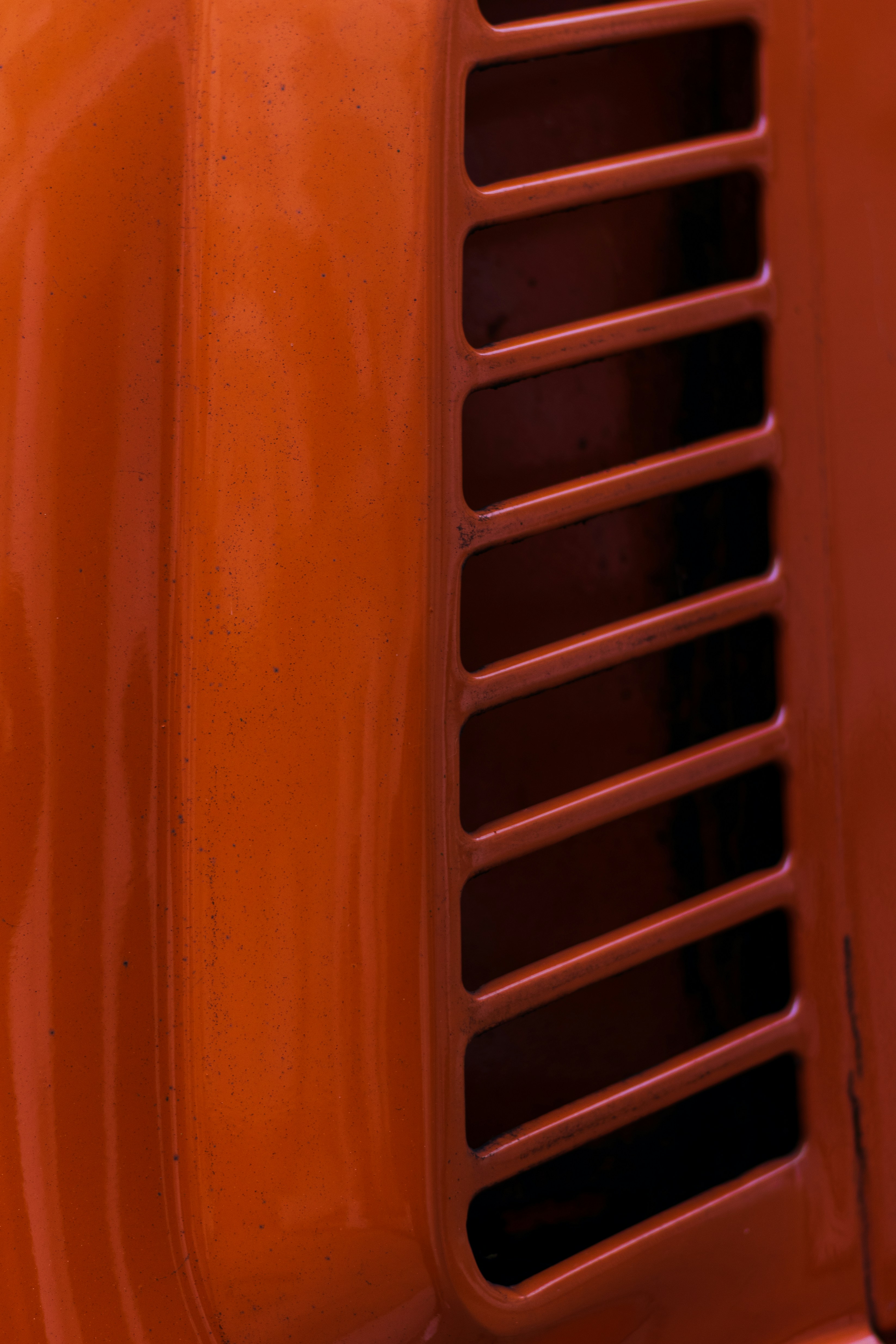 Crimson Slats: Close-Up of an Industrial Orange Vent
