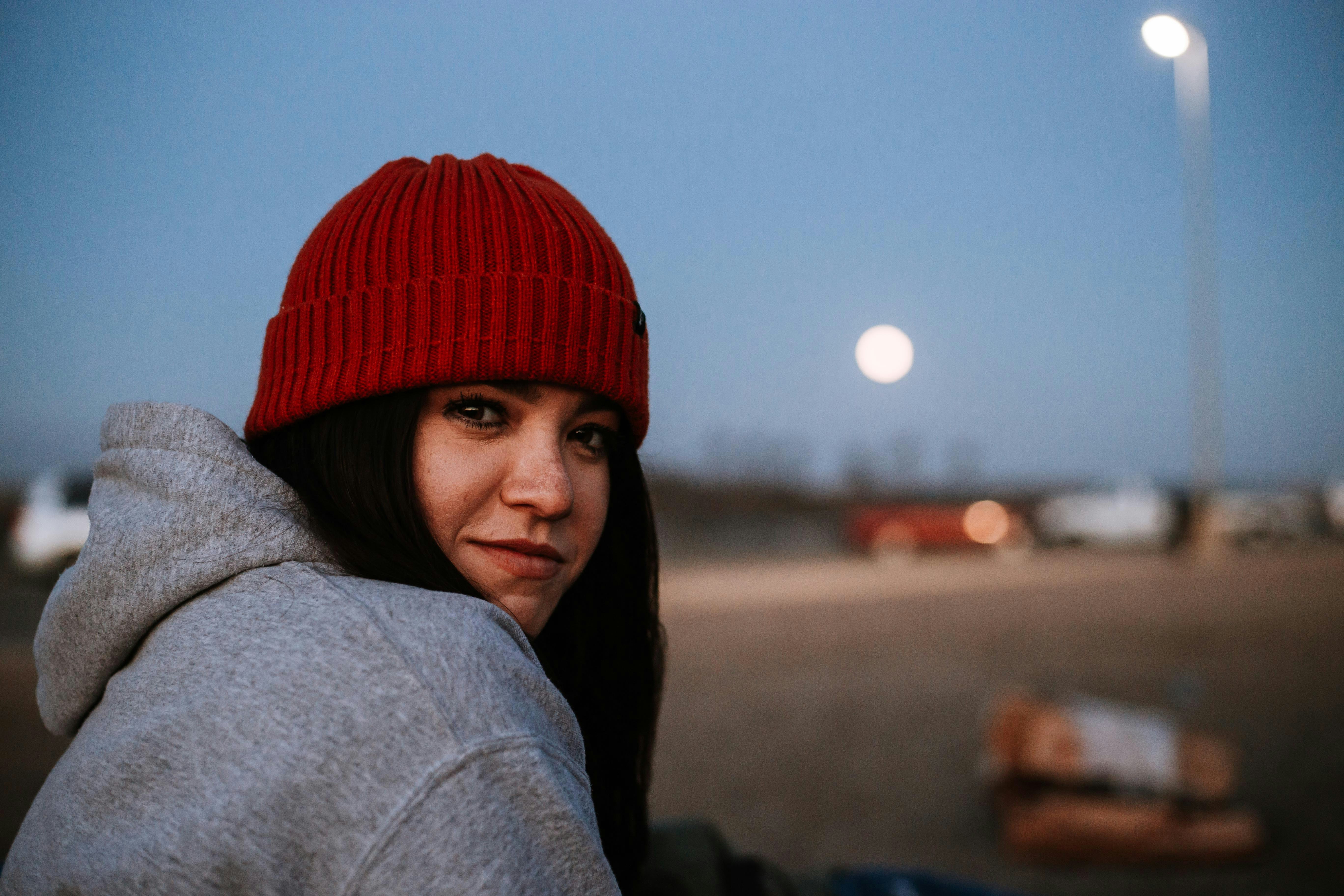 woman in gray hoodie wearing red knit cap