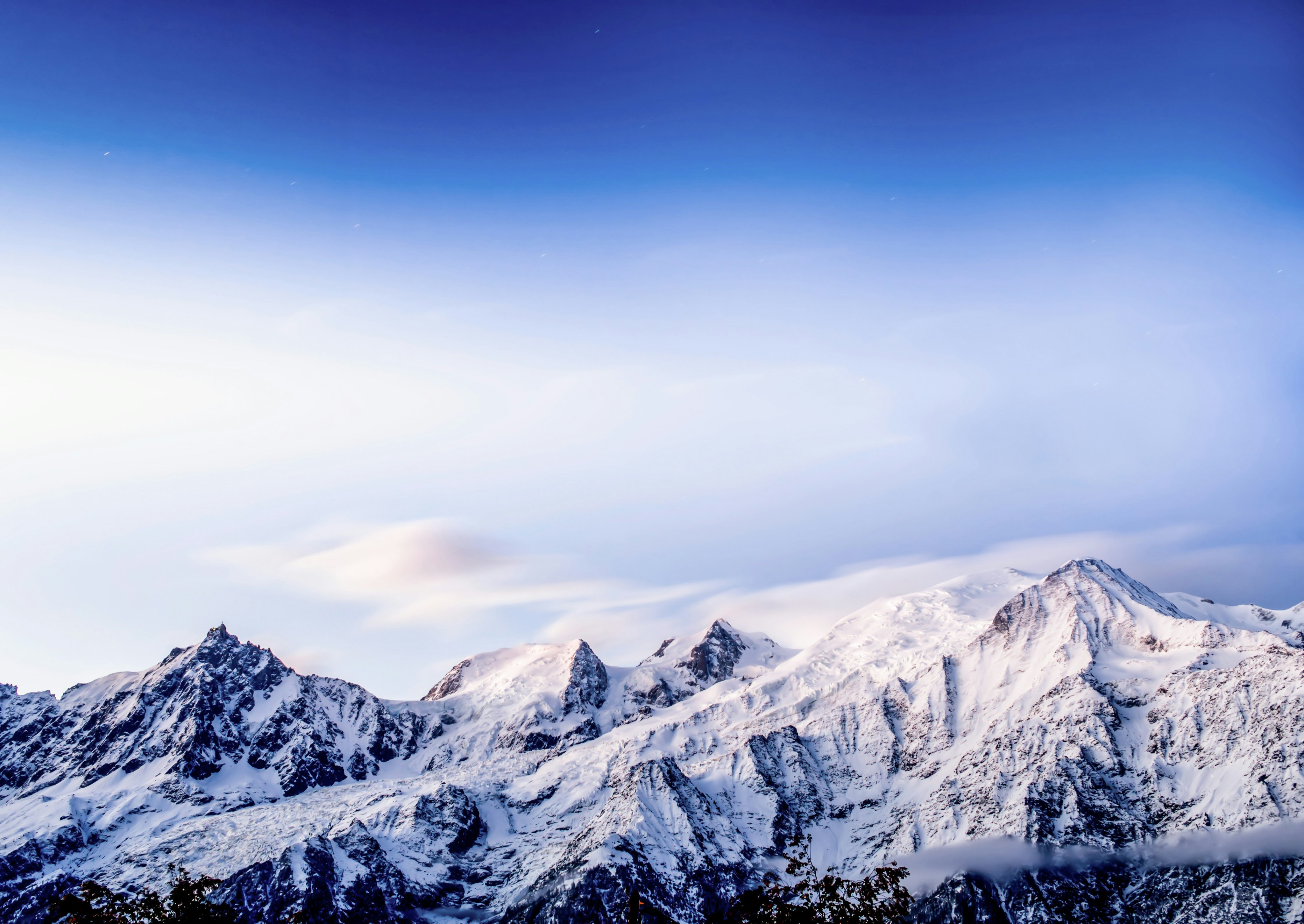 Majestic snow-capped mountains under a serene twilight sky, showcasing the peaceful transition from day to night.