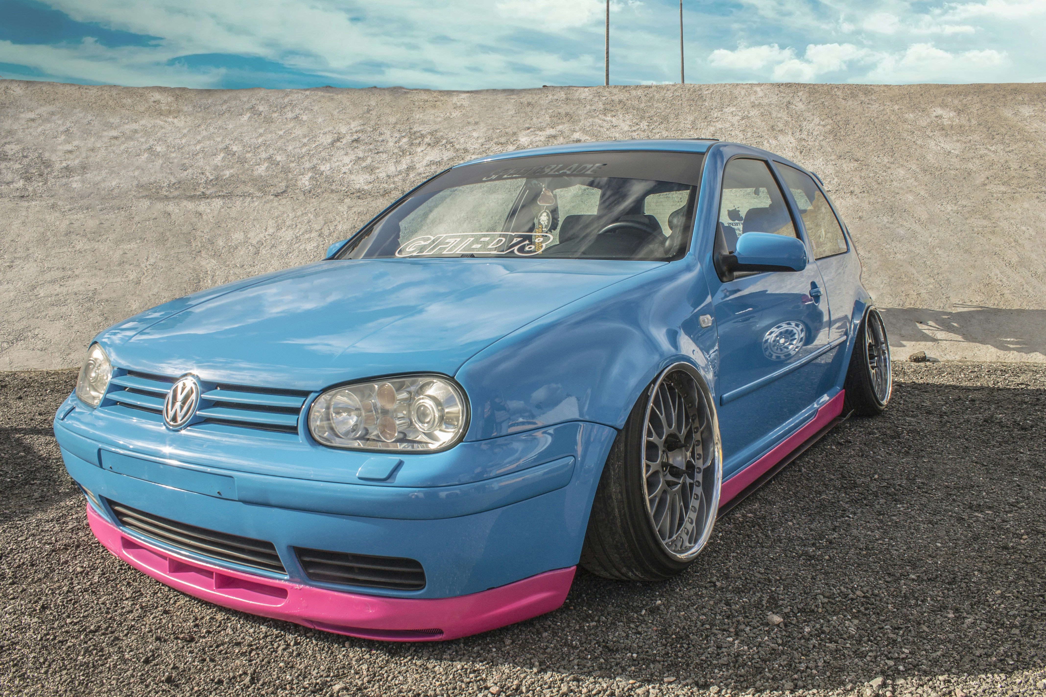 Blue VW Drift: Vibrant Hatch with Pink Accent under an Open Sky