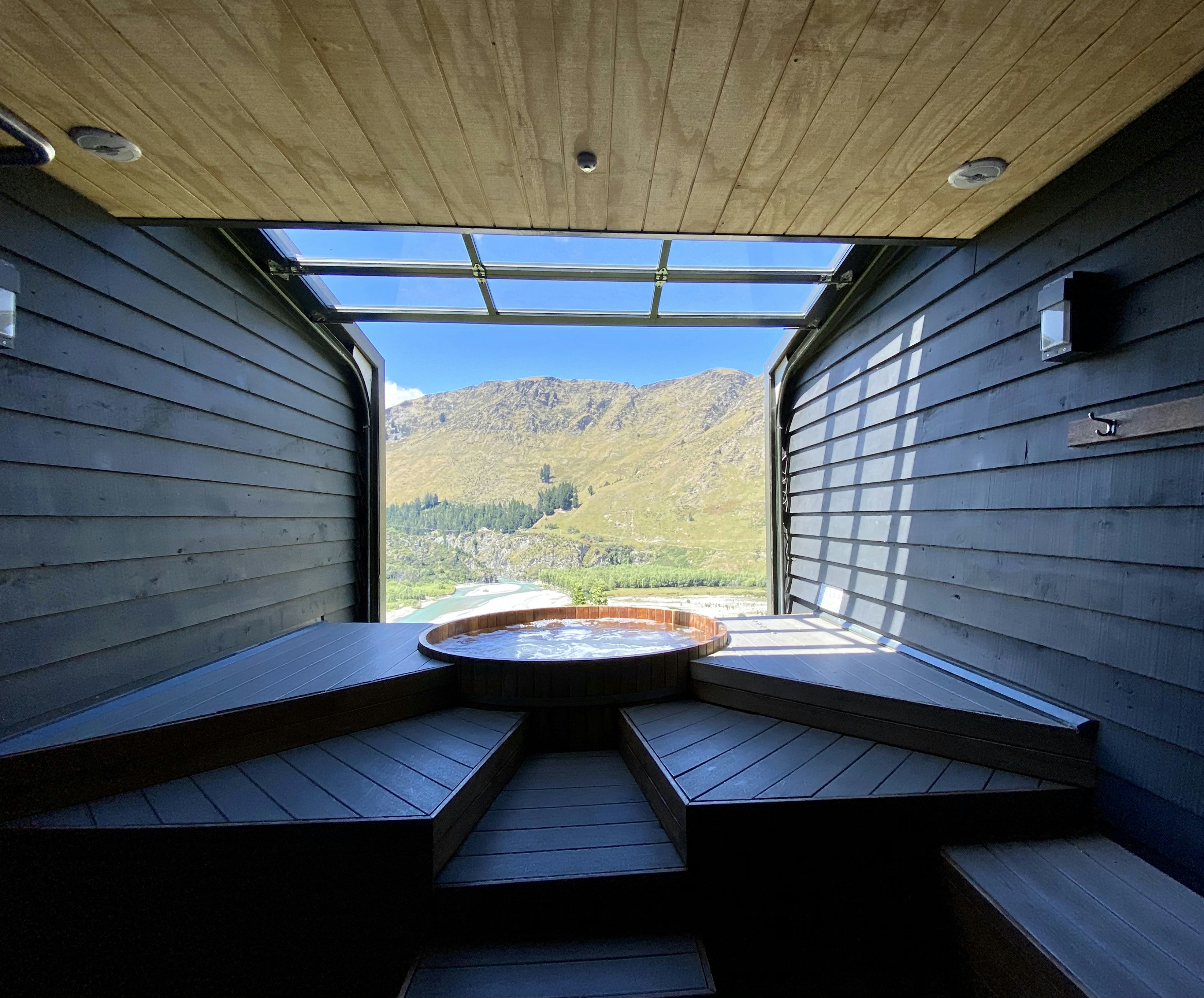 Inviting wooden spa area opens to breathtaking mountain landscape, showcasing a relaxing atmosphere and natural beauty.