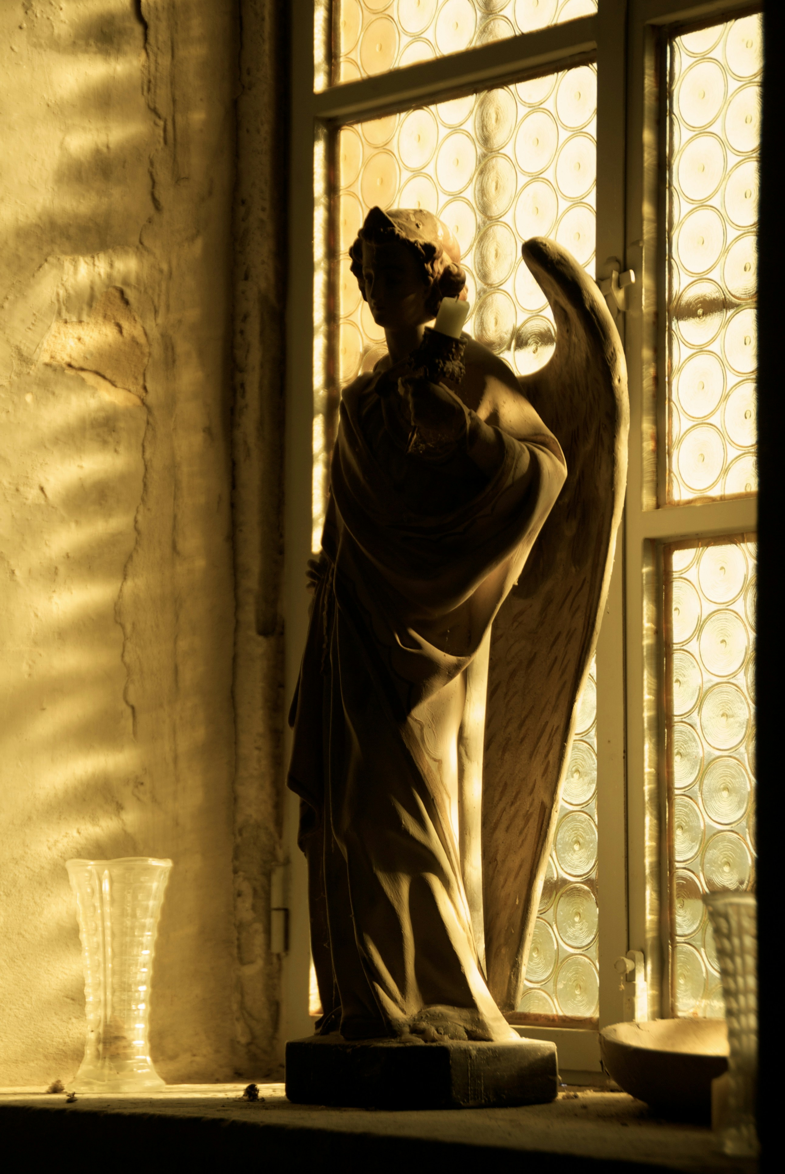 Angel Statue Silhouetted by Warm Glass Light