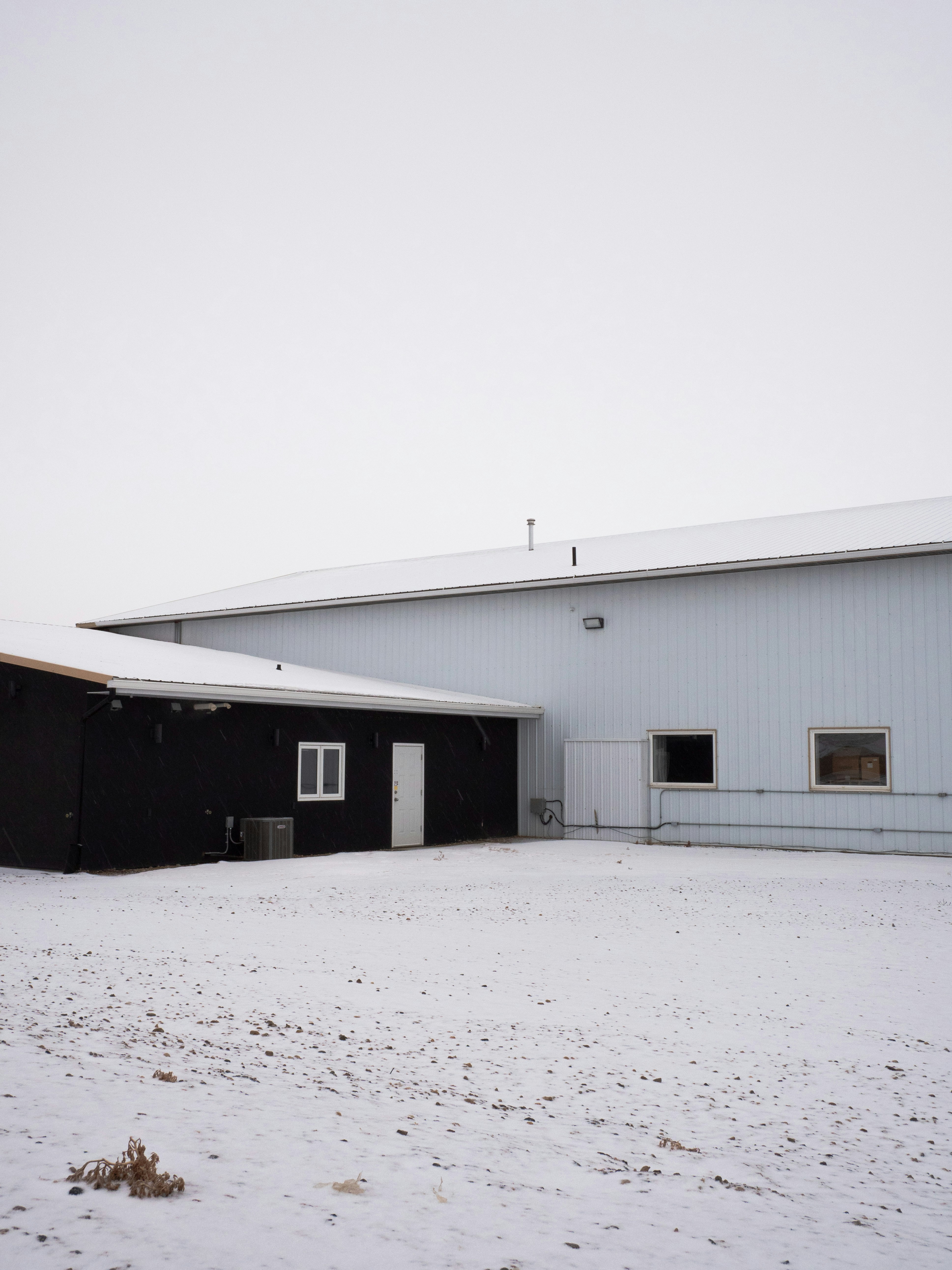 Minimal Industrial Landscape: Snow-Blanketed Blue Warehouse