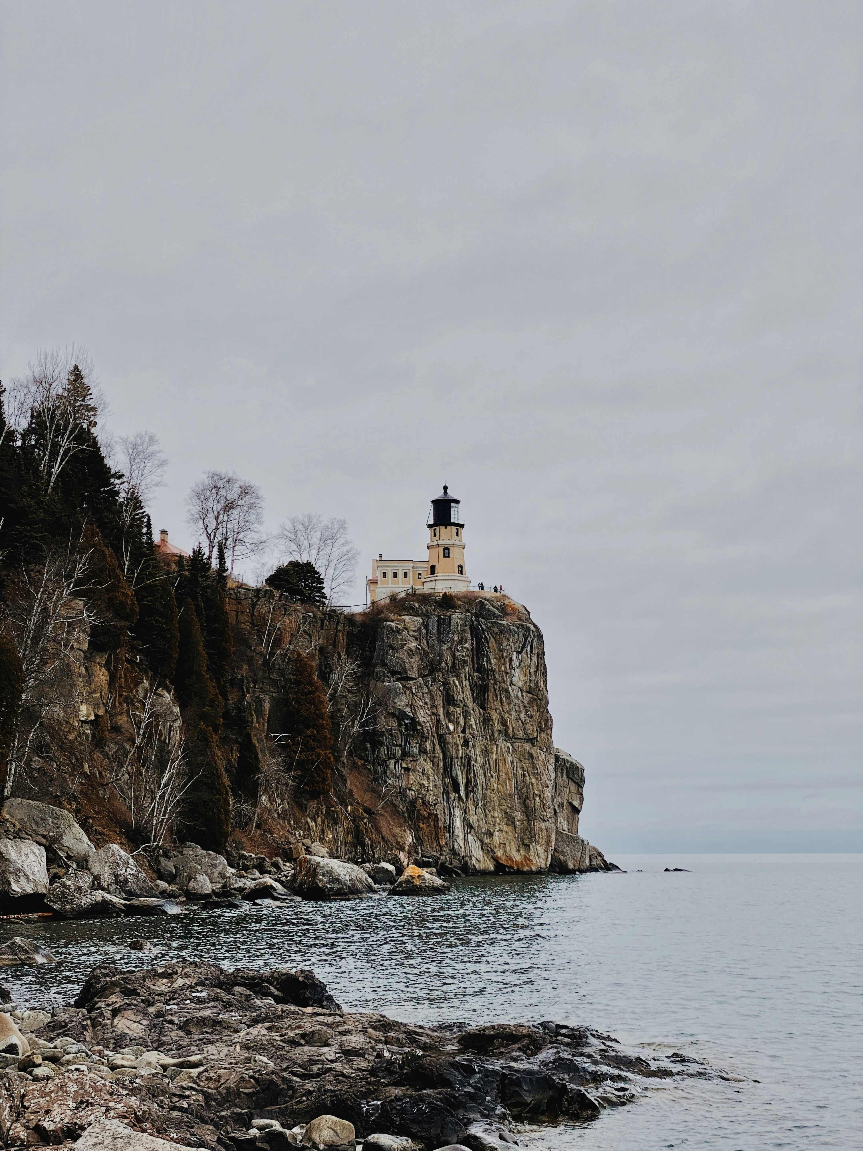 White lighthouse on brown rock formation near body of water during ...