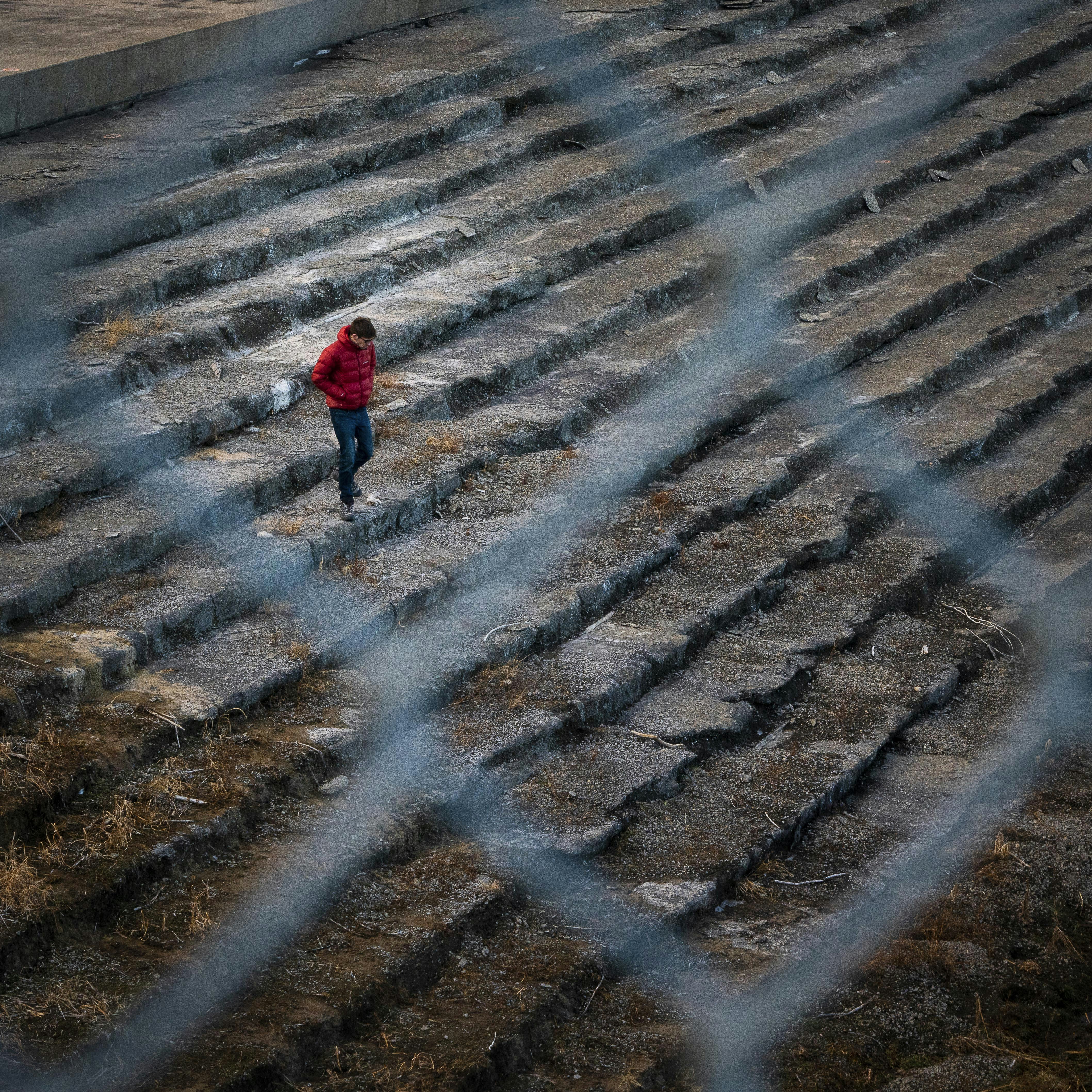 Red-clad Wanderer on Weathered Terraces Framed by a Diamond Fence