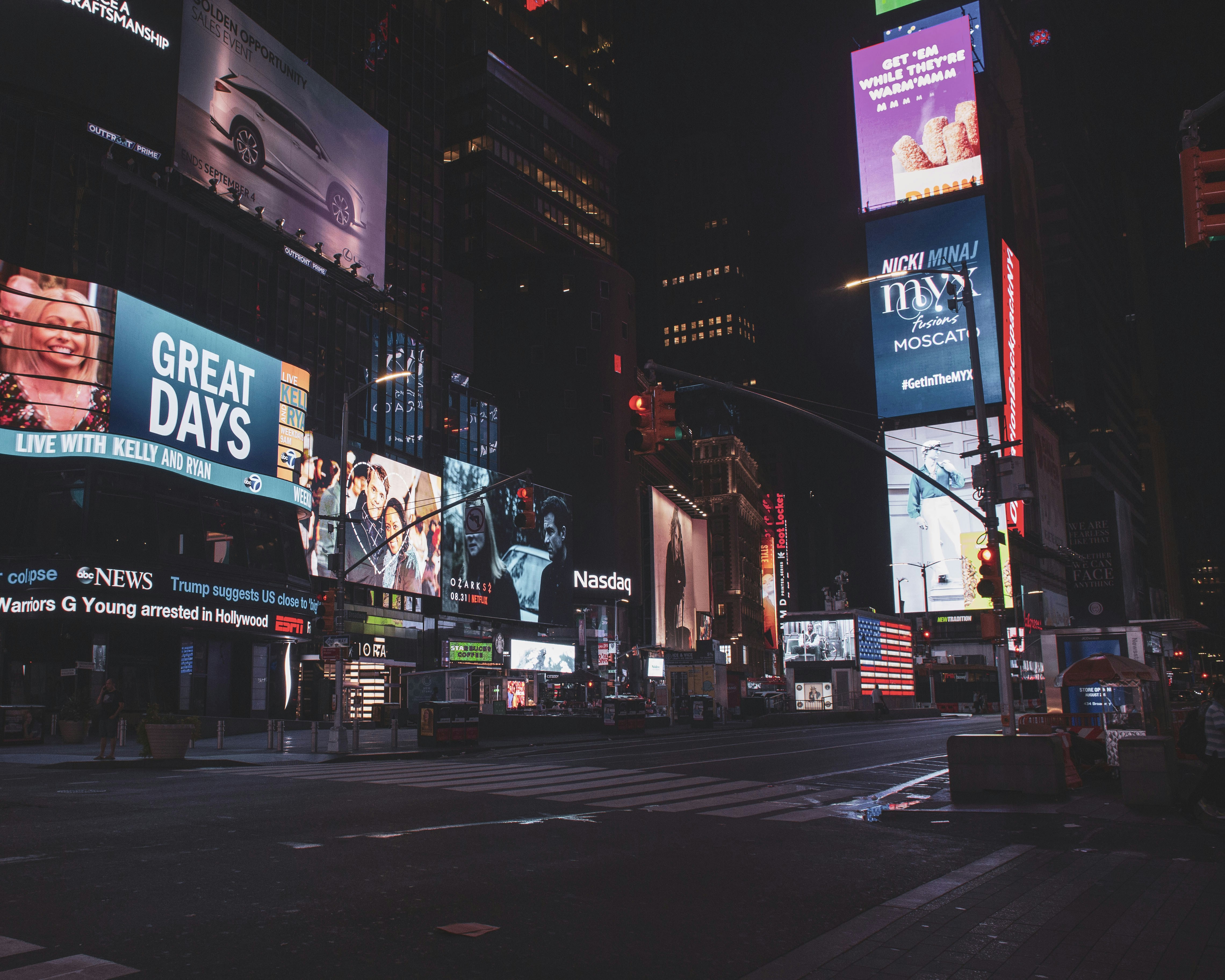 Vibrant billboards illuminate a quiet Times Square at night, showcasing various advertisements and city energy.