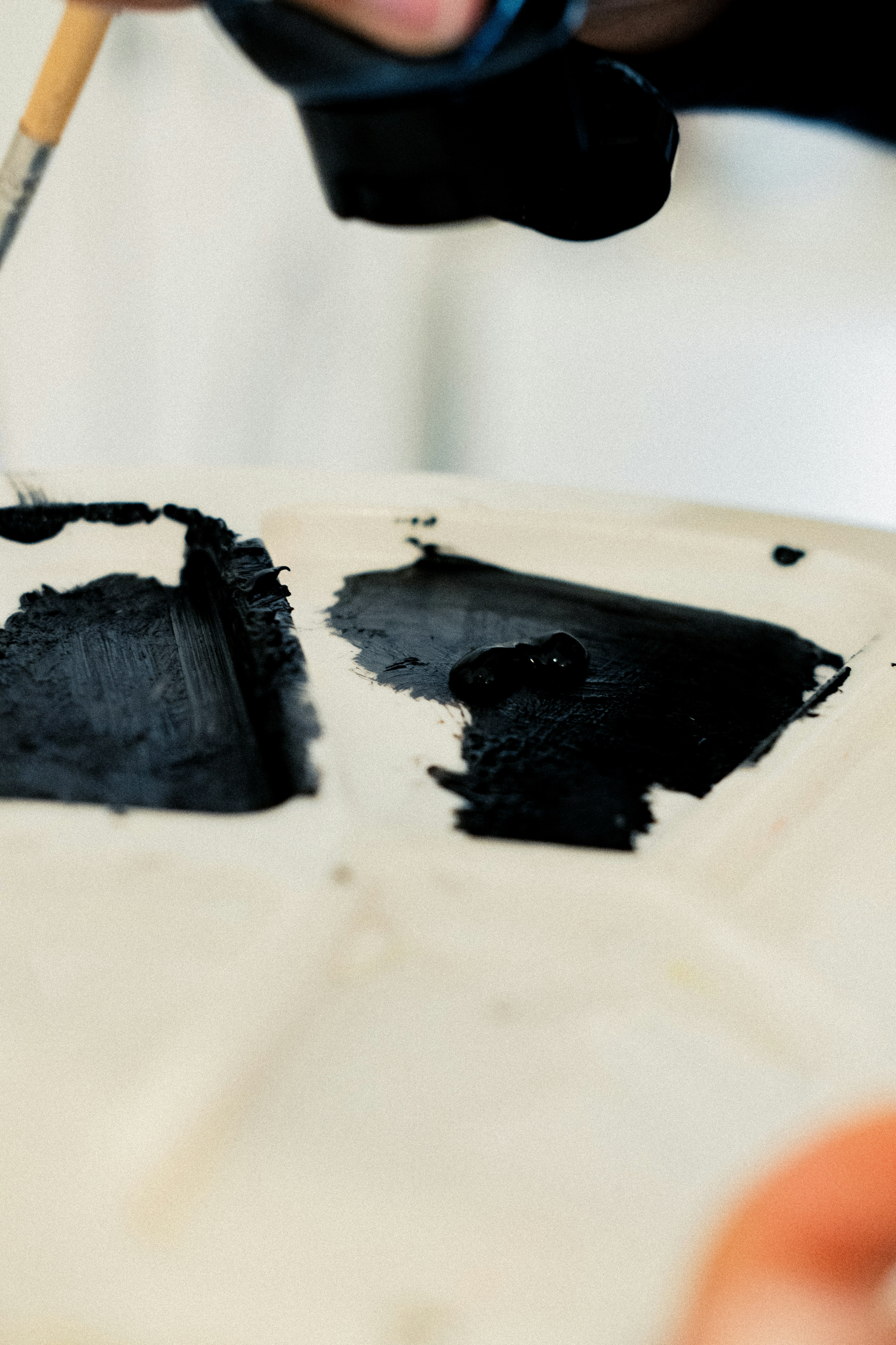 Close-Up Strokes: Black Paint on a Cream Palette in Quiet Detail
