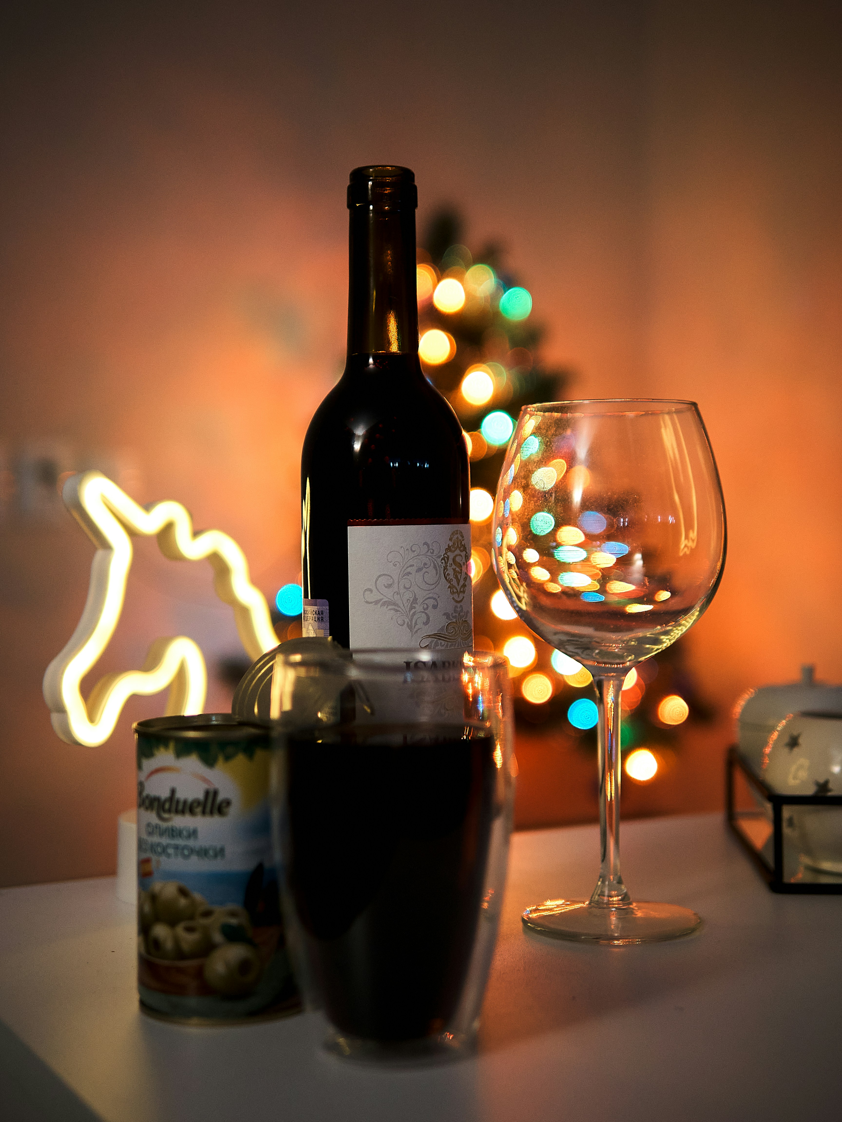 Centerpiece in Warm Bokeh: Red Wine Bottle Amid Neon Accent and Holiday Lights