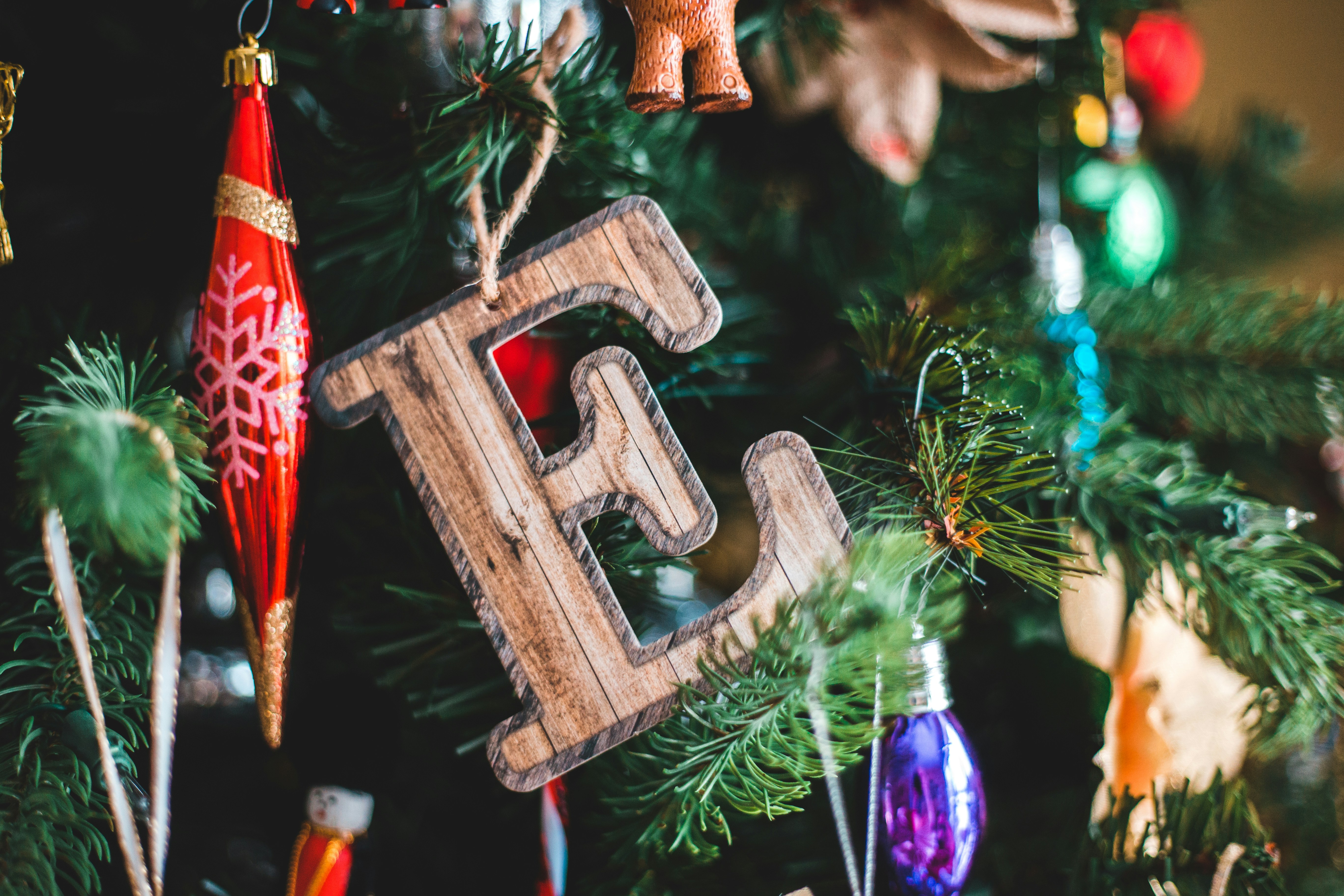 Wooden Letter E Dangles Amid Christmas Glow: A Close-Up of Rustic Ornament Charm