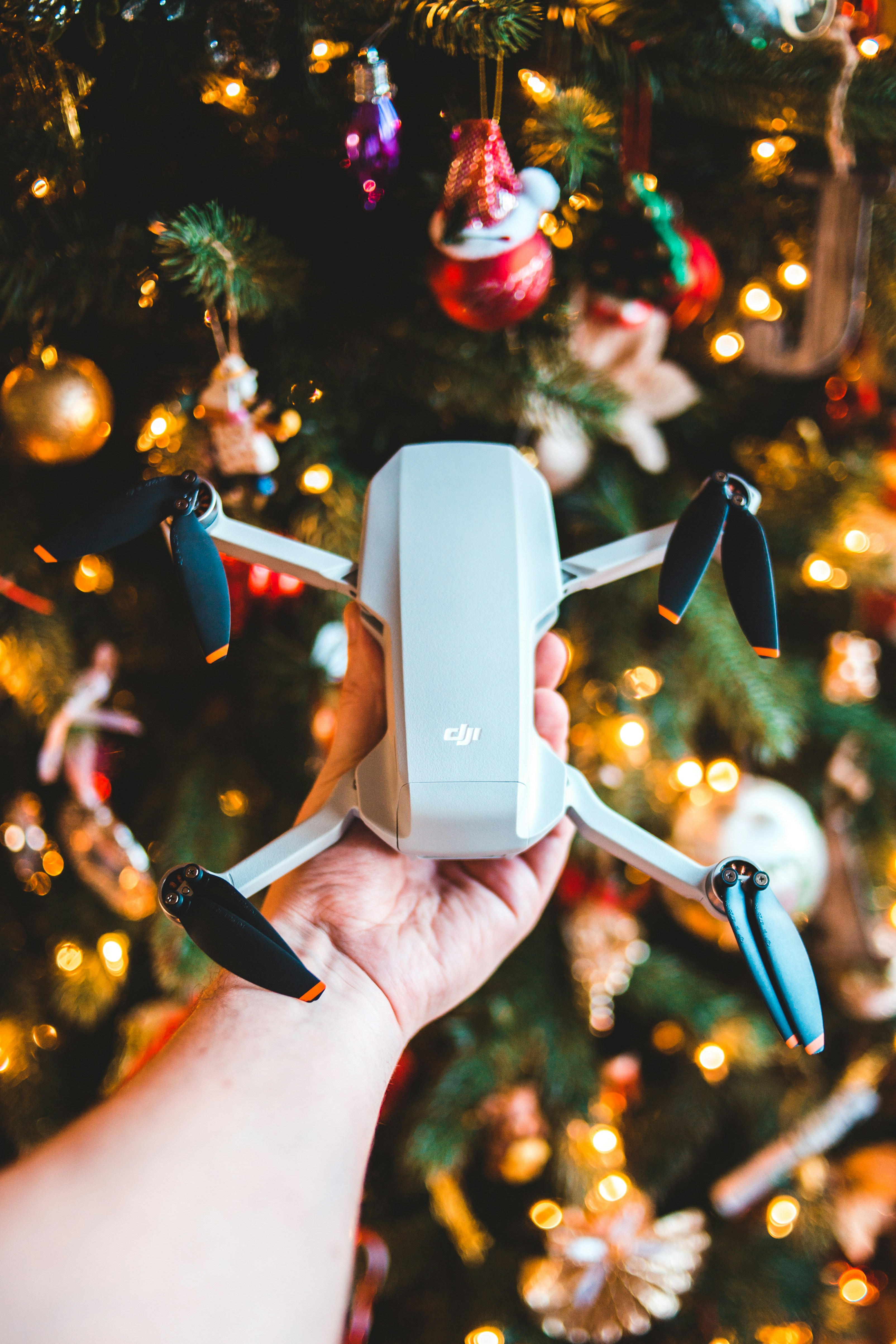 Holiday in Hand: A Compact Drone Framed by a Festive Tree