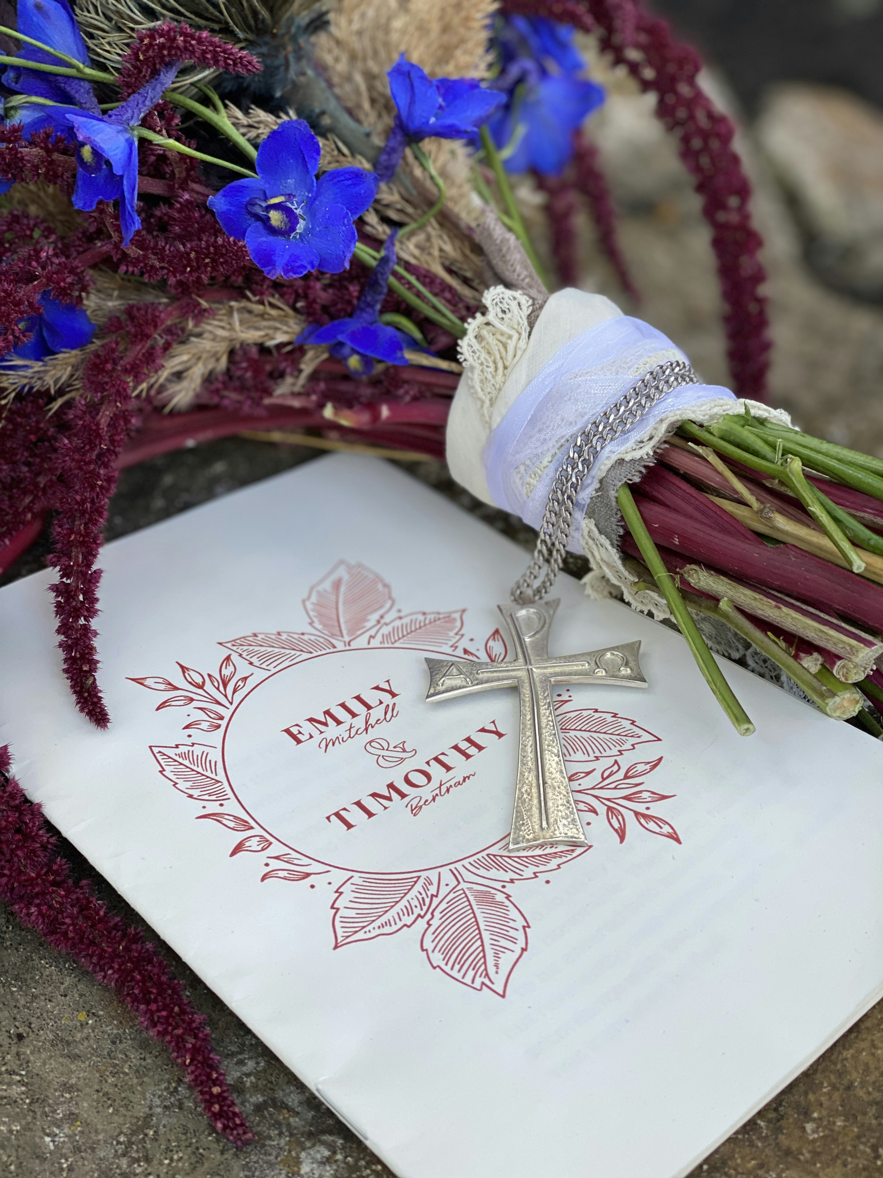 Cross Pendant over a Wedding Invitation Nestled in a Bouquet