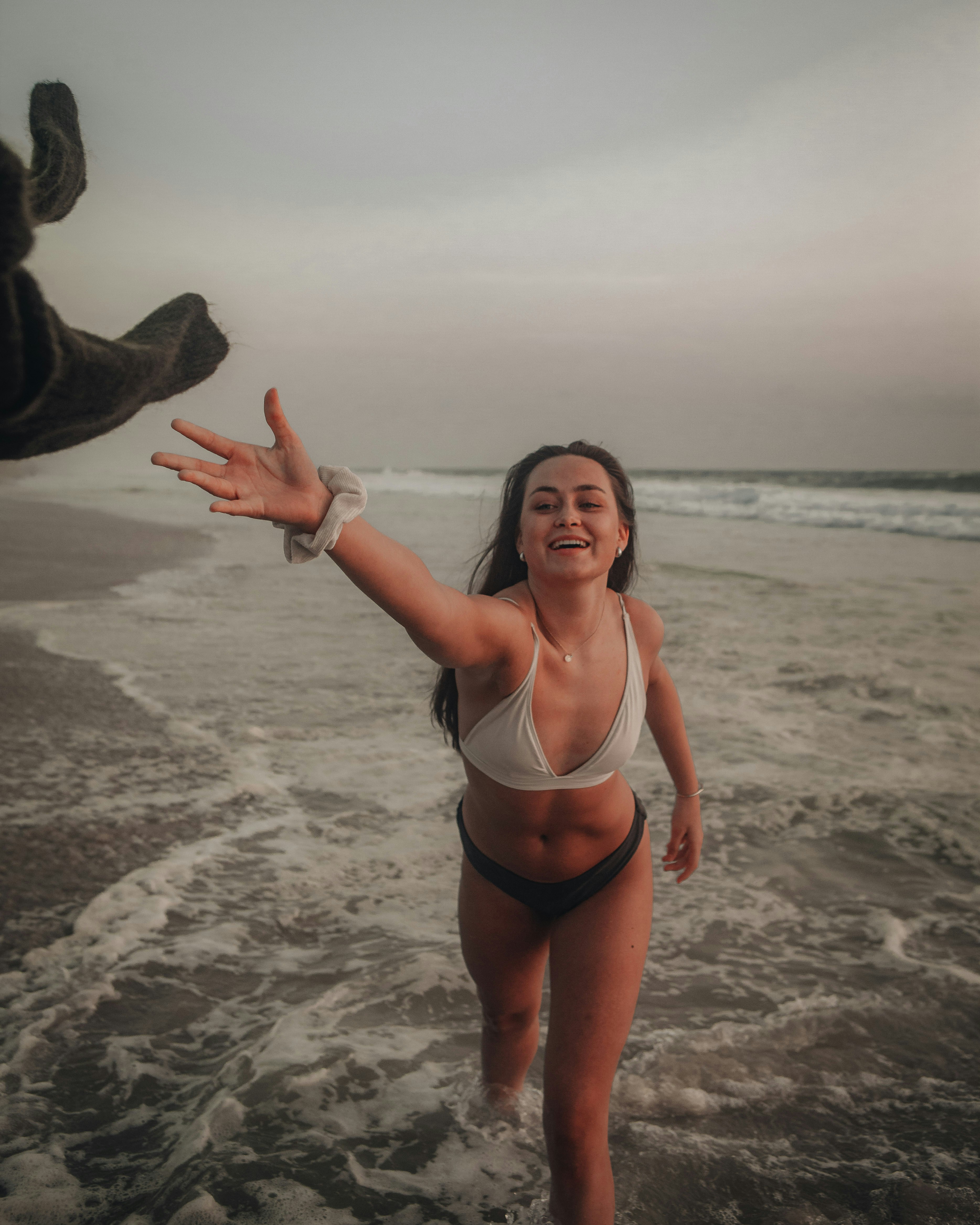 Reaching Toward the Tide: A Beach Moment with a Joyful Smile