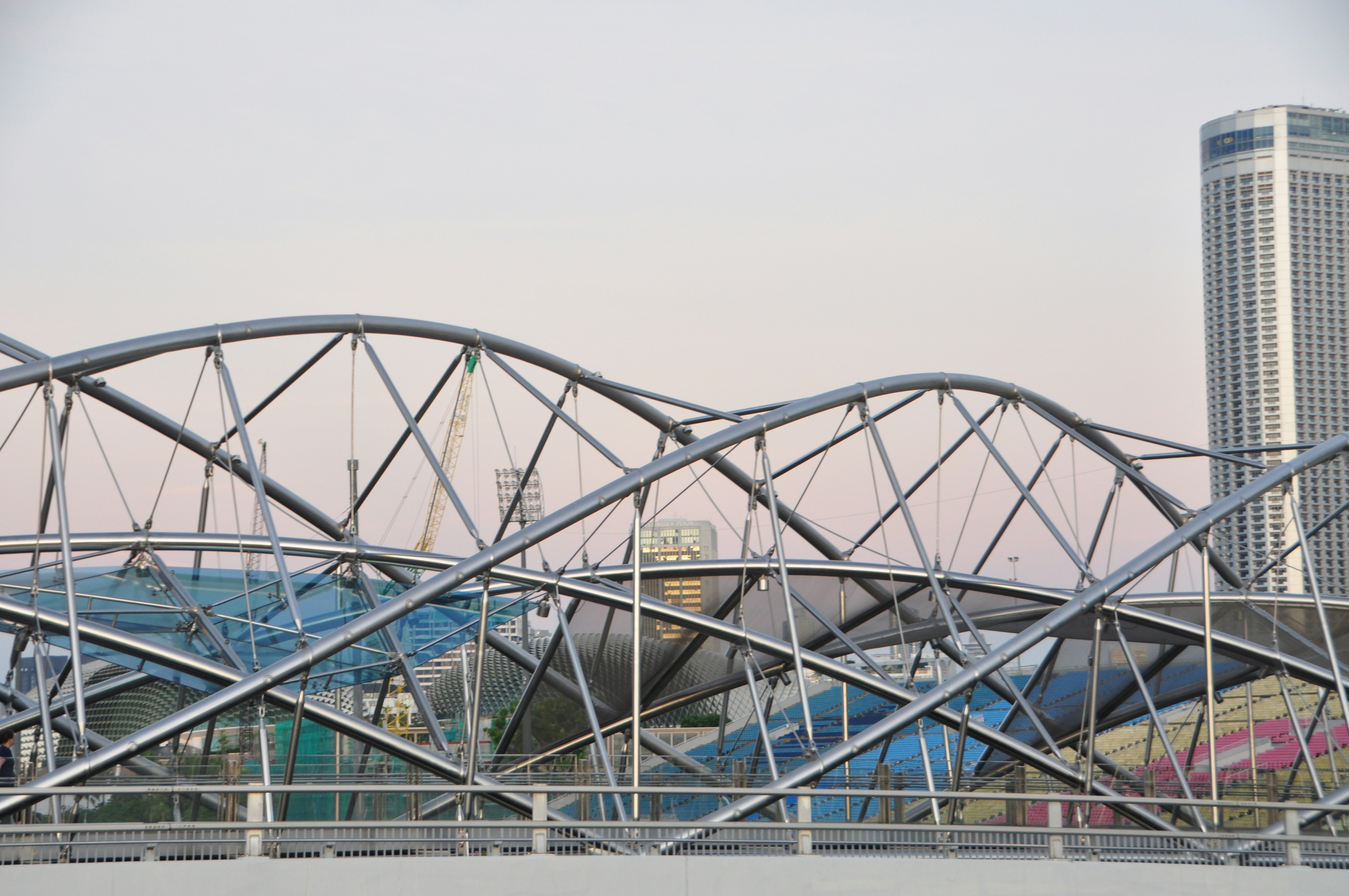 Intricate steel structure of a modern bridge against a pastel sky, showcasing urban architecture and engineering. 