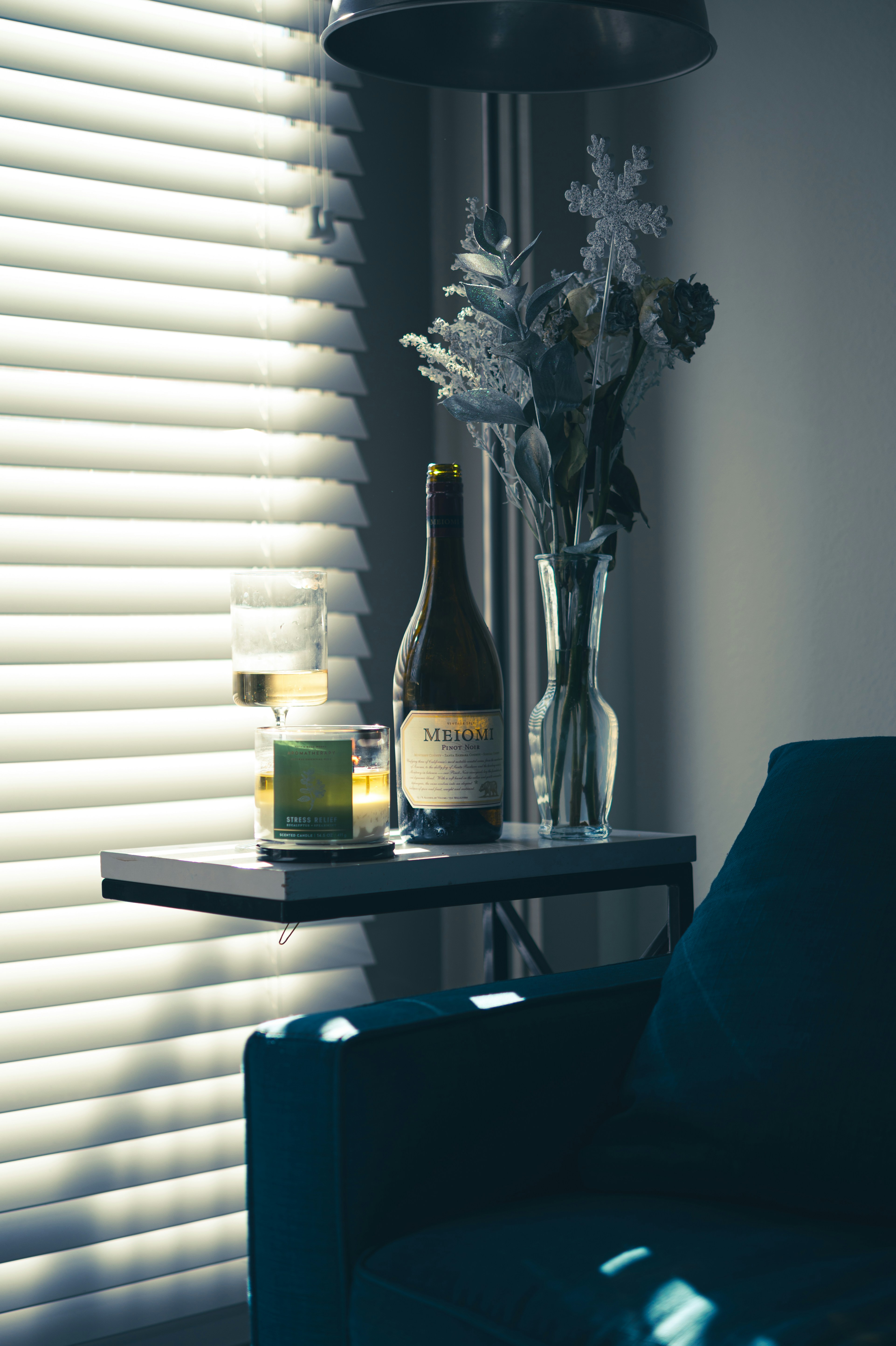Blue Hour Still Life: A Wine Bottle, Candle and Frosted Florals by Window