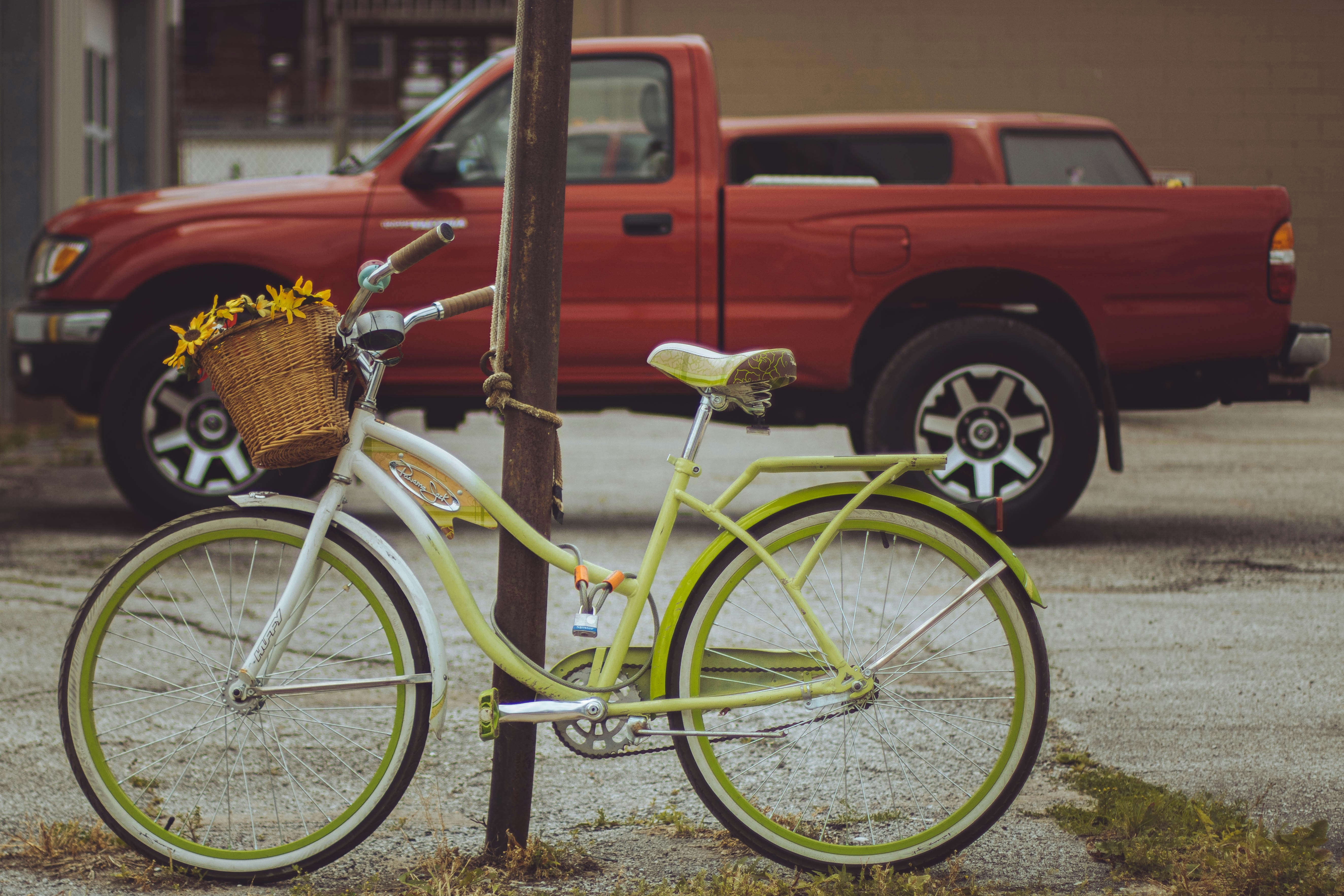 Lemon-Hued Vintage Bicycle by a Lamppost: Flowers in a Basket, Red Truck in the Background