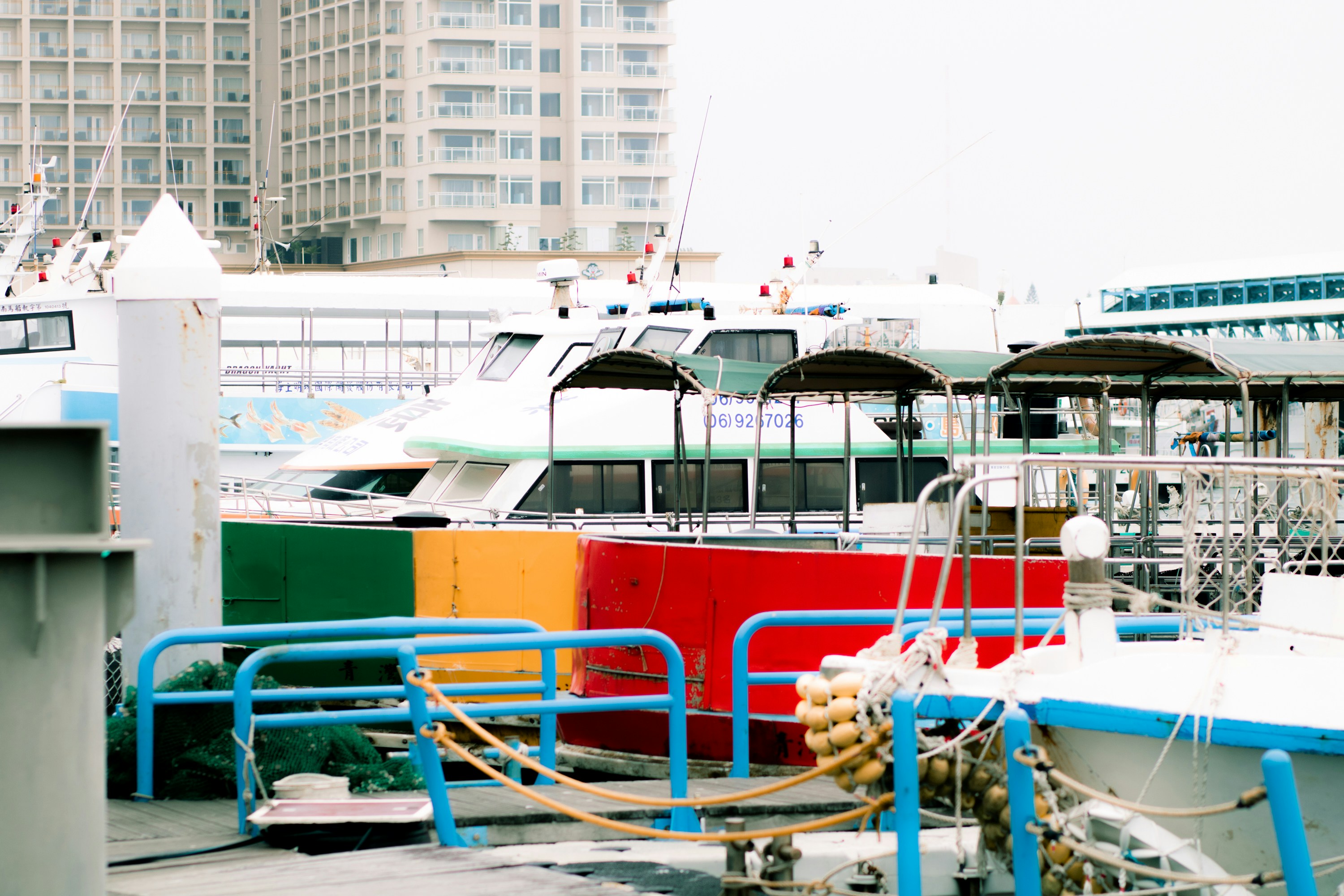 Colorful boats docked at a bustling harbor, surrounded by modern architecture. The scene captures the essence of maritime activity.