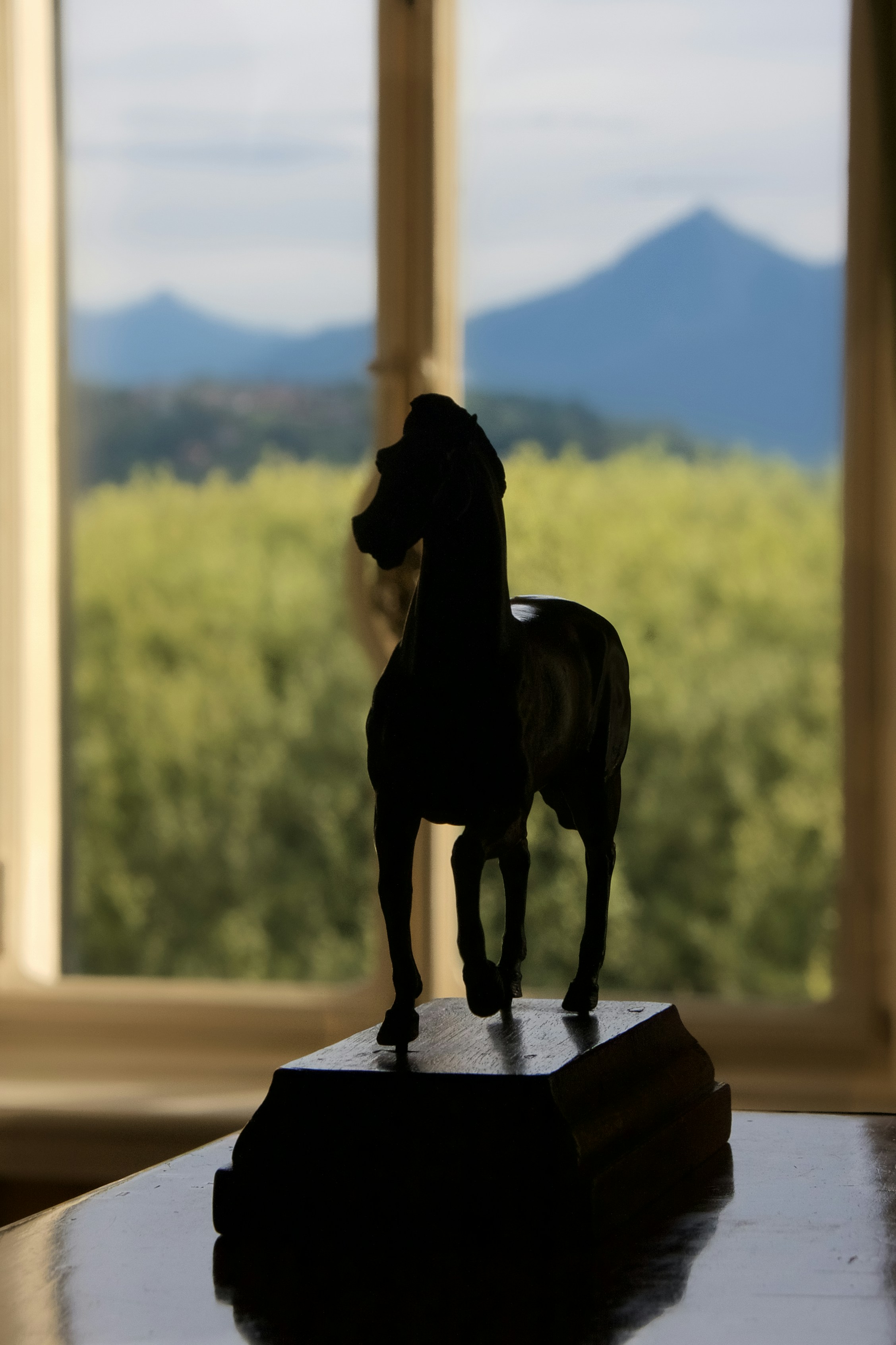Silhouette on a Pedestal: A Horse Figurine Framed by Distant Hills