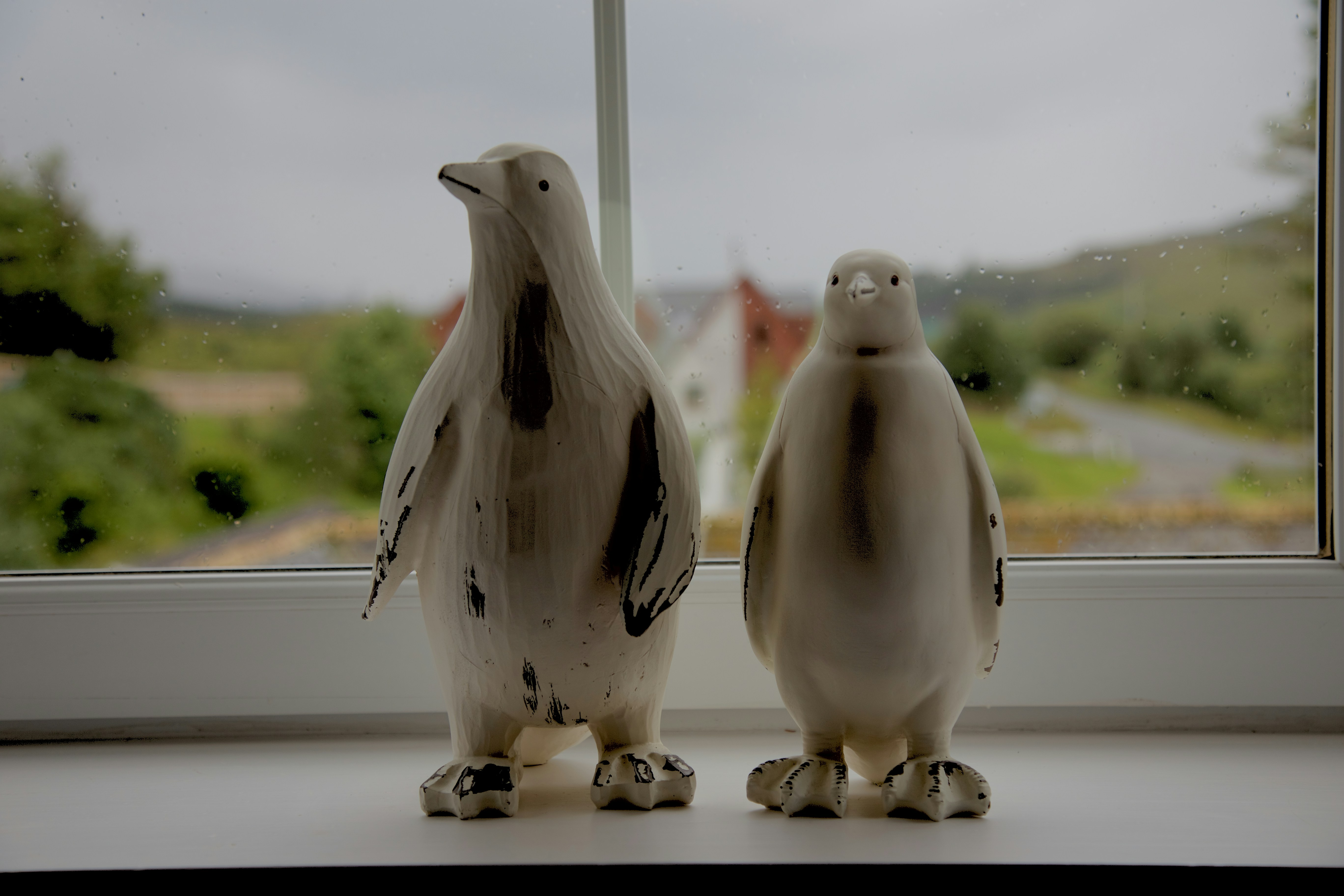 Two Porcelain Pigeons on a Windowsill with a Soft-Focused Countryside