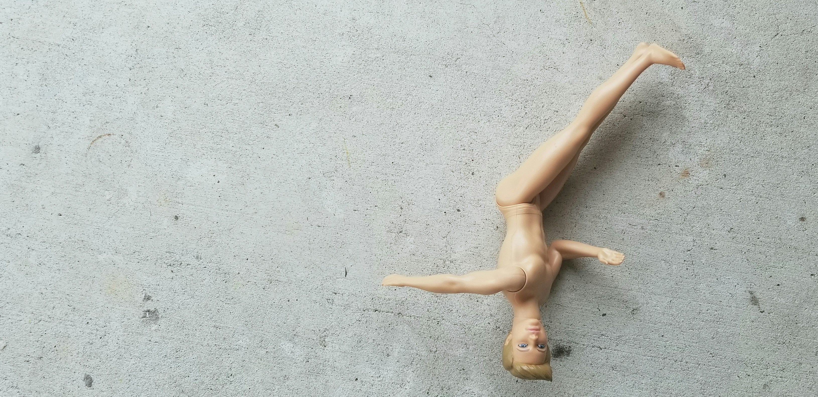 Concrete Still-Life: A Plastic Figure Poised in an Off-Balance Moment