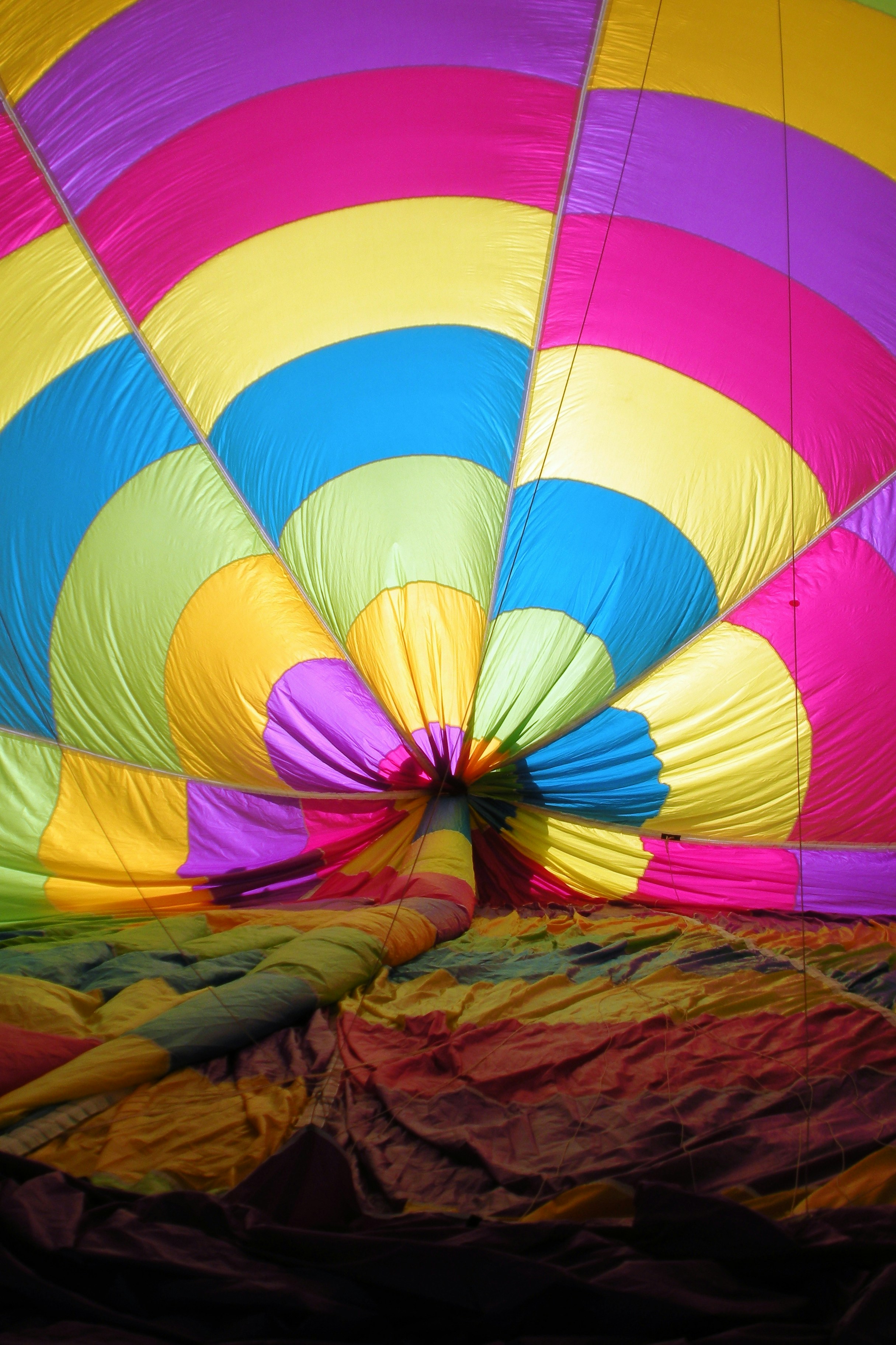 Inside a multicolored hot air balloon envelope, fabric panels spiral toward a central cone, creating a vibrant convergence of pink, yellow, blue, and green.