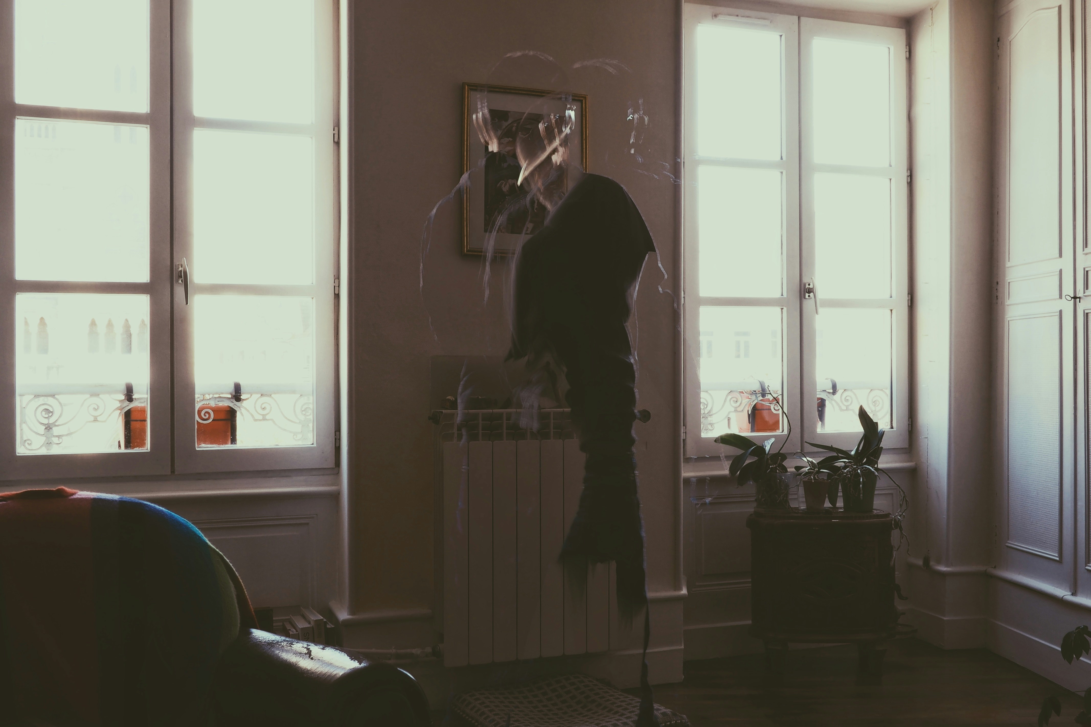 Silhouette in a Sunlit Apartment: A Quiet Moment with Glass Bottles