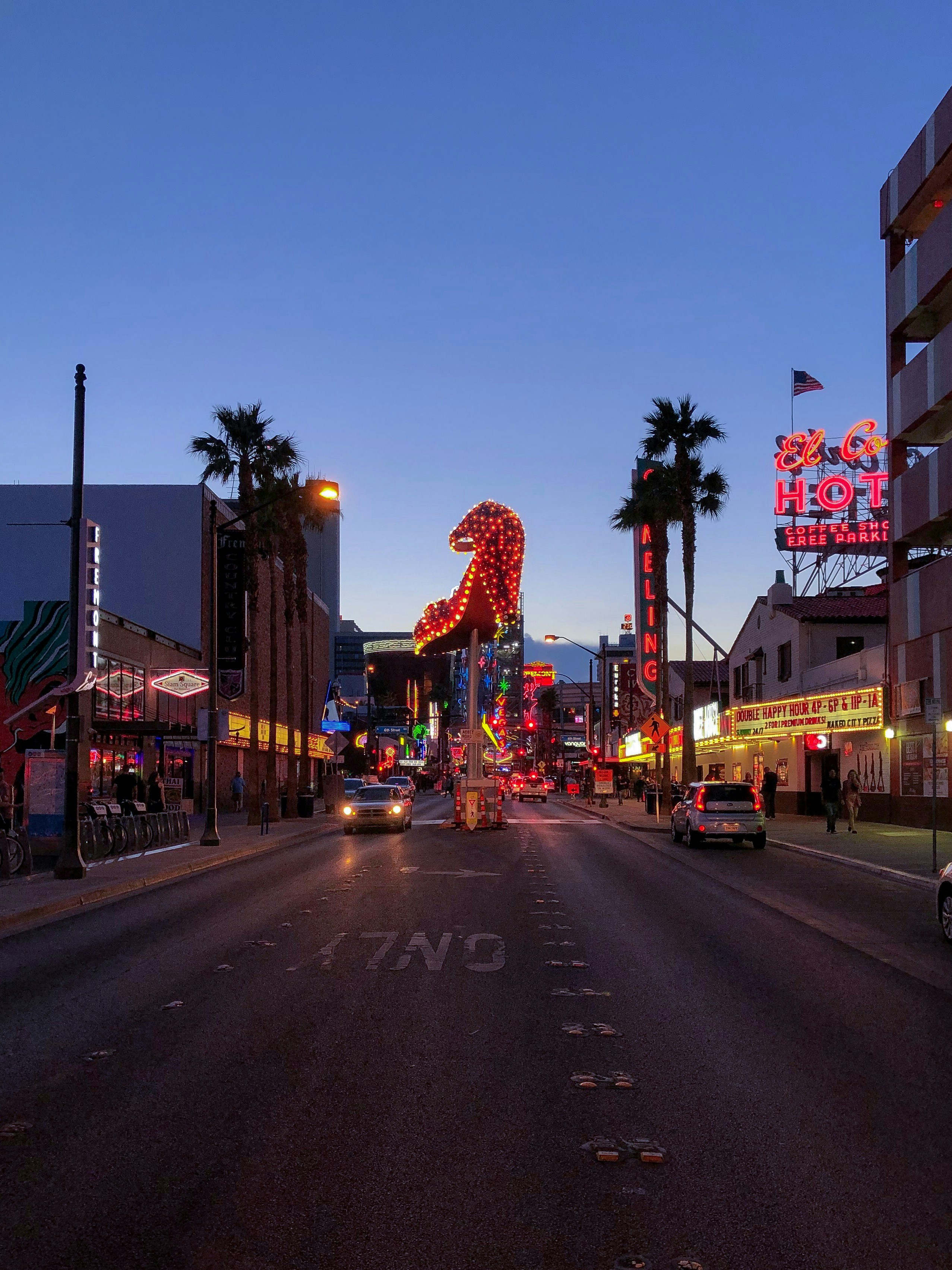 Vibrant neon signs illuminate a bustling street scene at twilight, showcasing the lively atmosphere of a city known for its nightlife.
