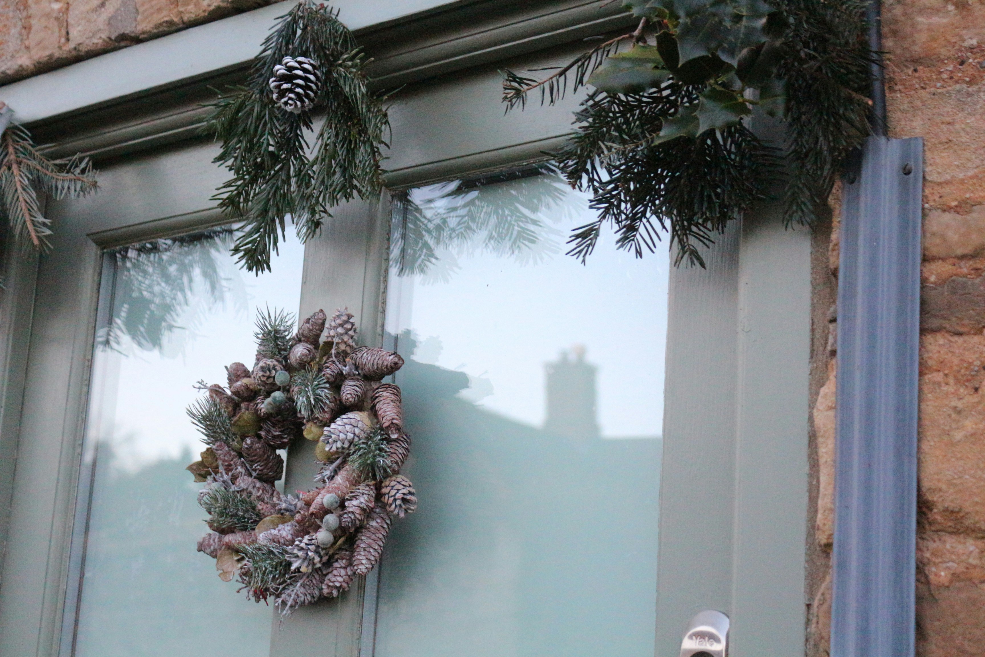 Winter wreath framed by frosted glass and evergreen garlands