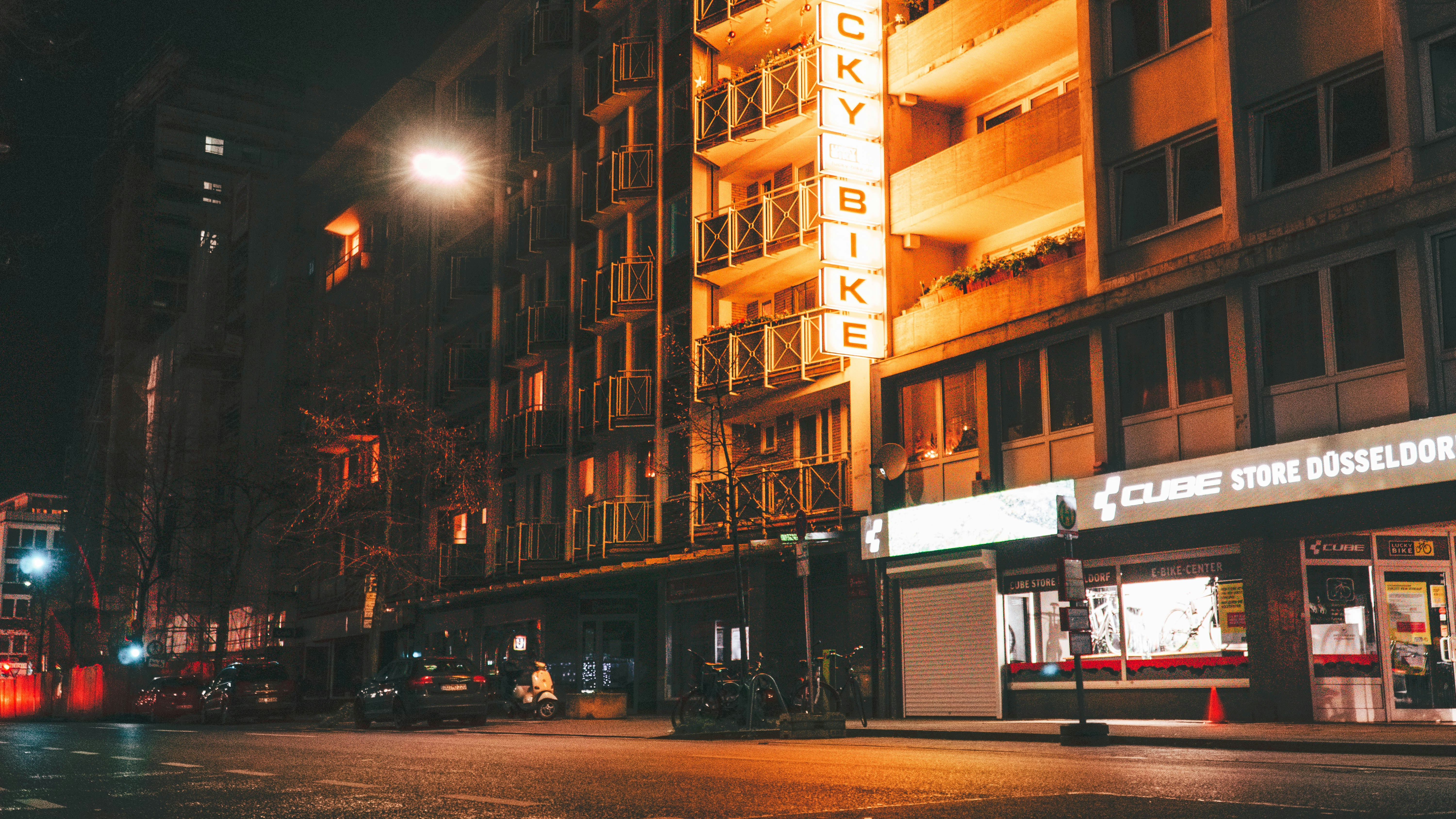 Illuminated building with a prominent bike rental sign against a nighttime city backdrop, showcasing urban life and architecture.
