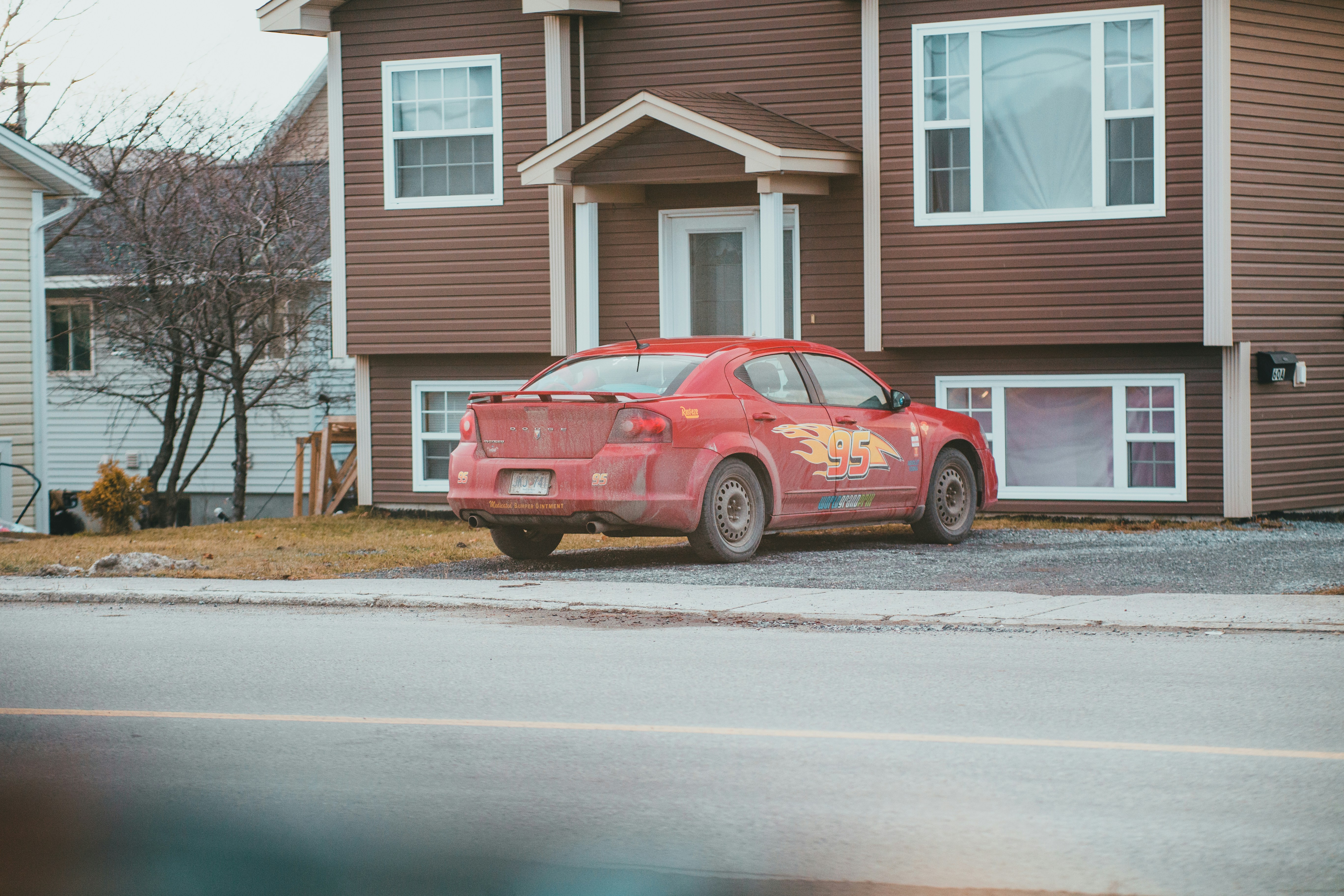 Red Lightning on the Driveway: A Lightning-bolt Car Pops Against a Quiet Suburban House