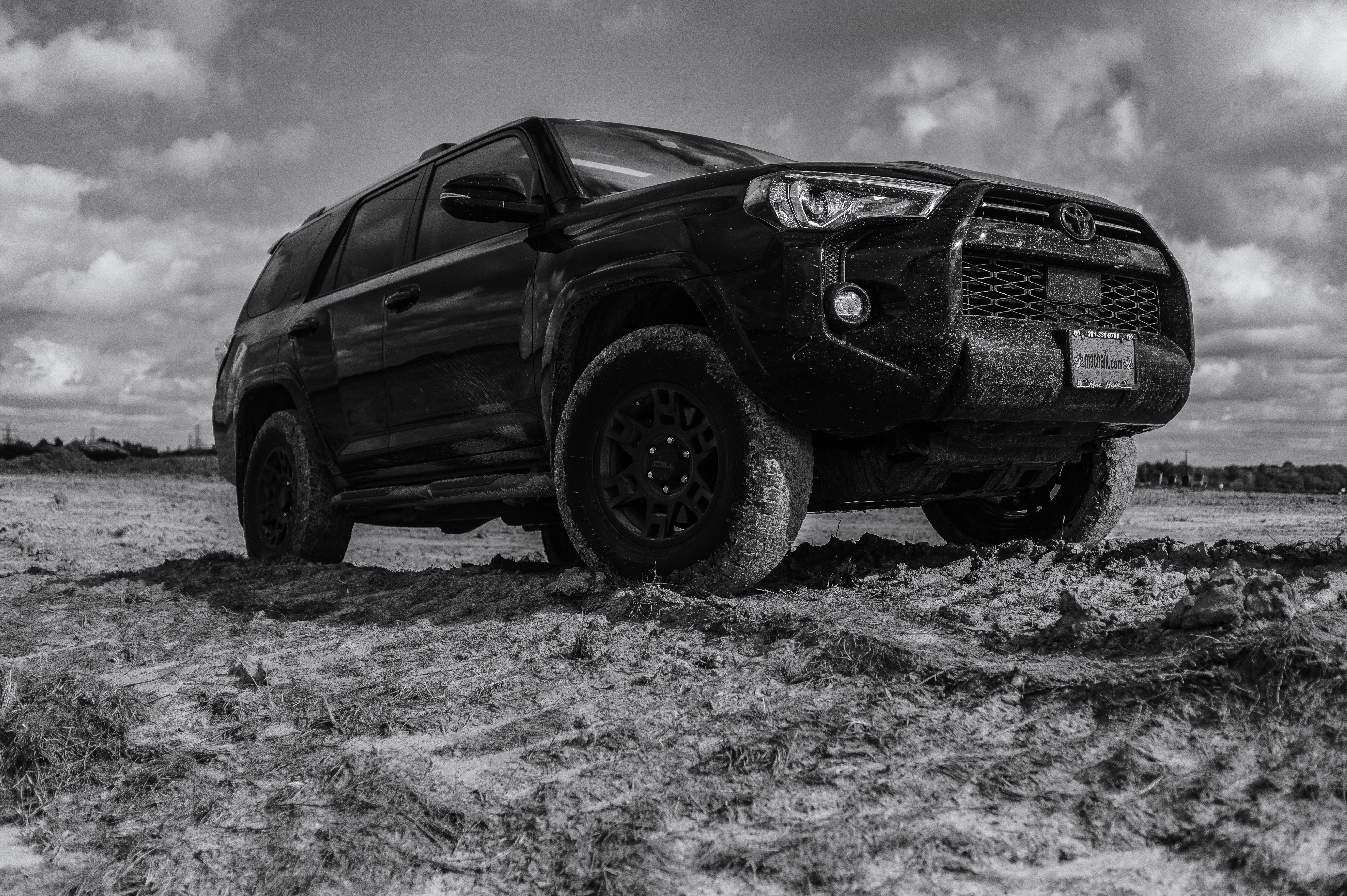 Toyota 4Runner navigating muddy terrain under a cloudy sky.