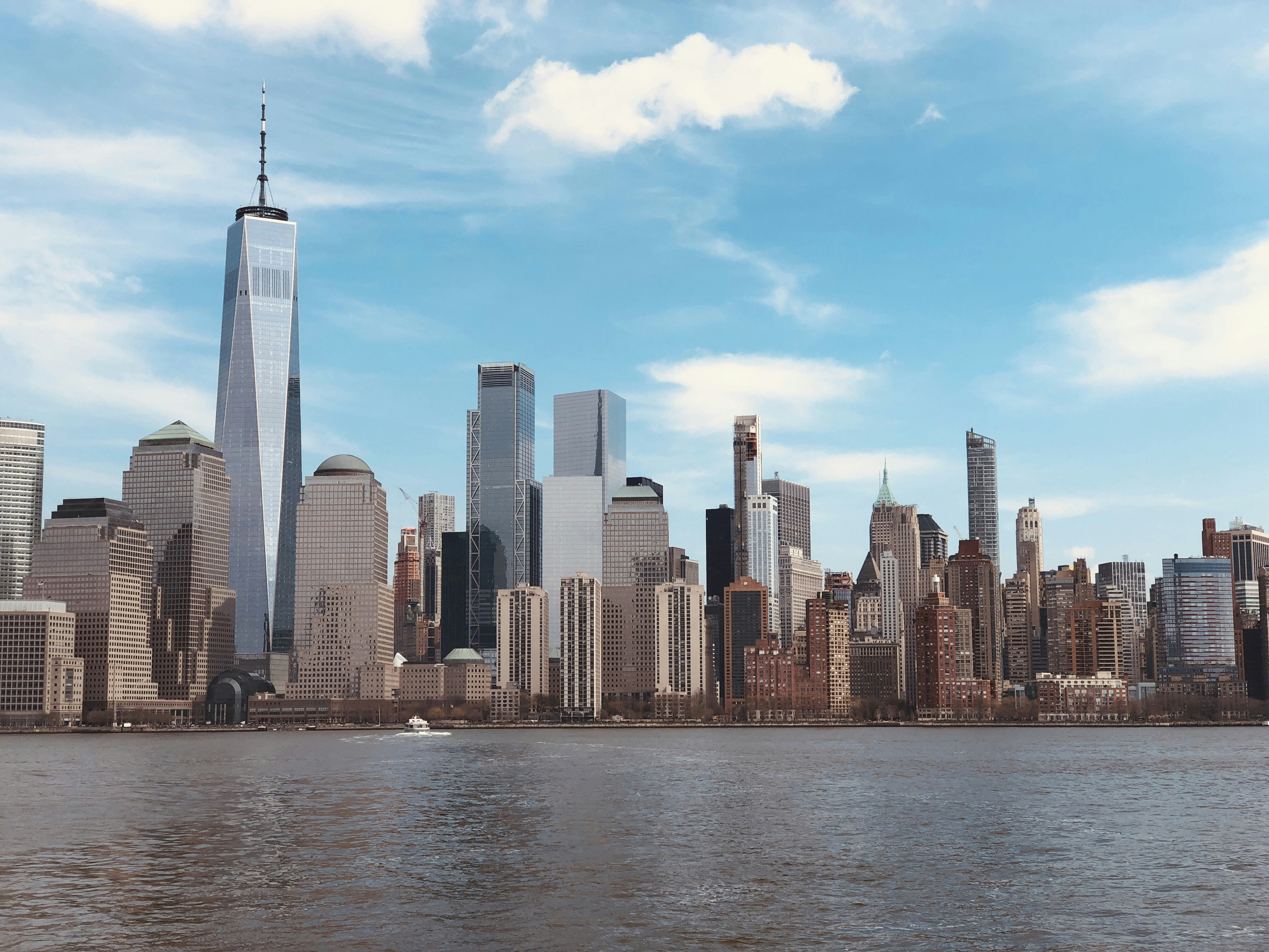 New York City skyline with towering skyscrapers under a bright blue sky.