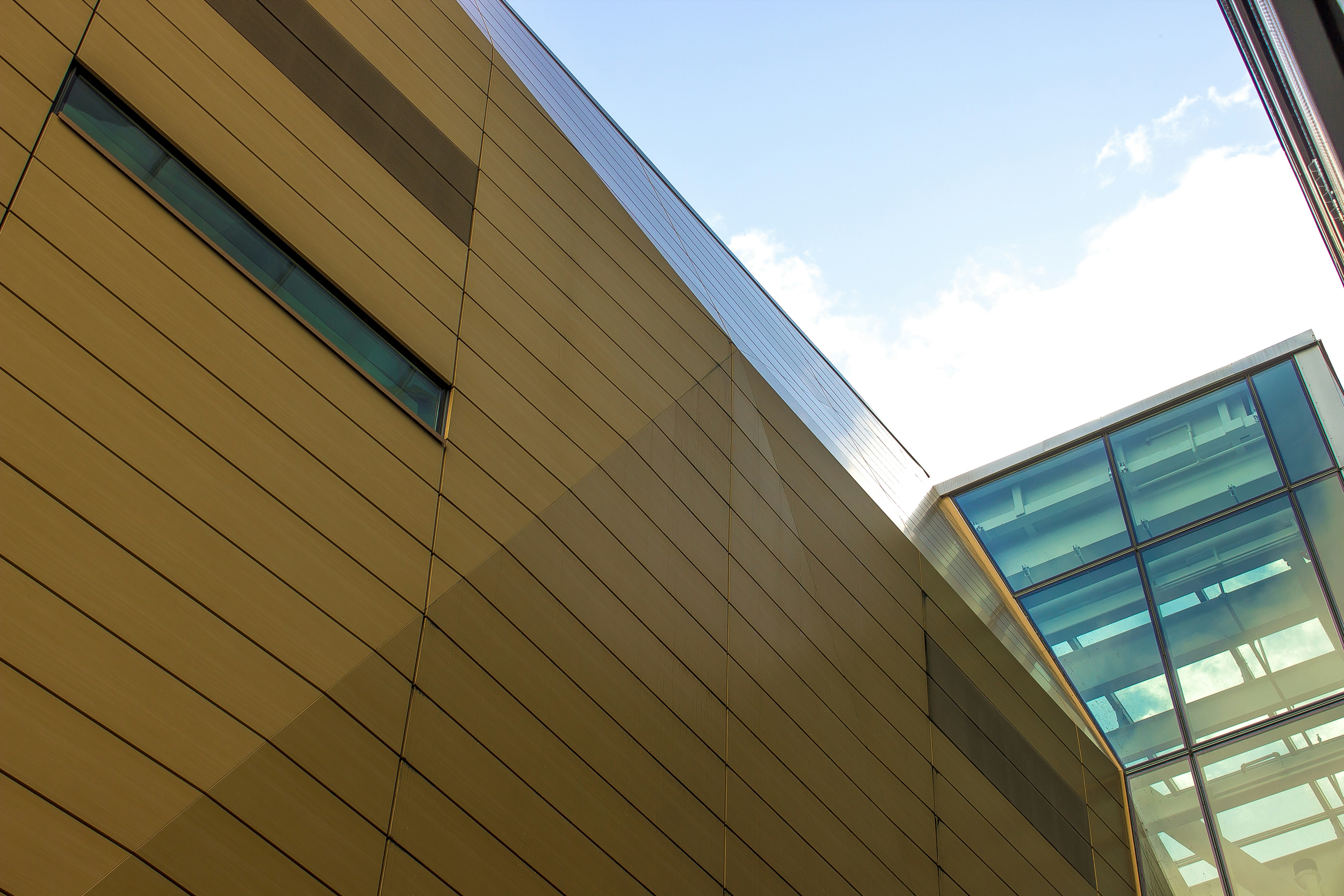 Angular view of a contemporary building showcasing a blend of metal and glass elements against a bright sky.