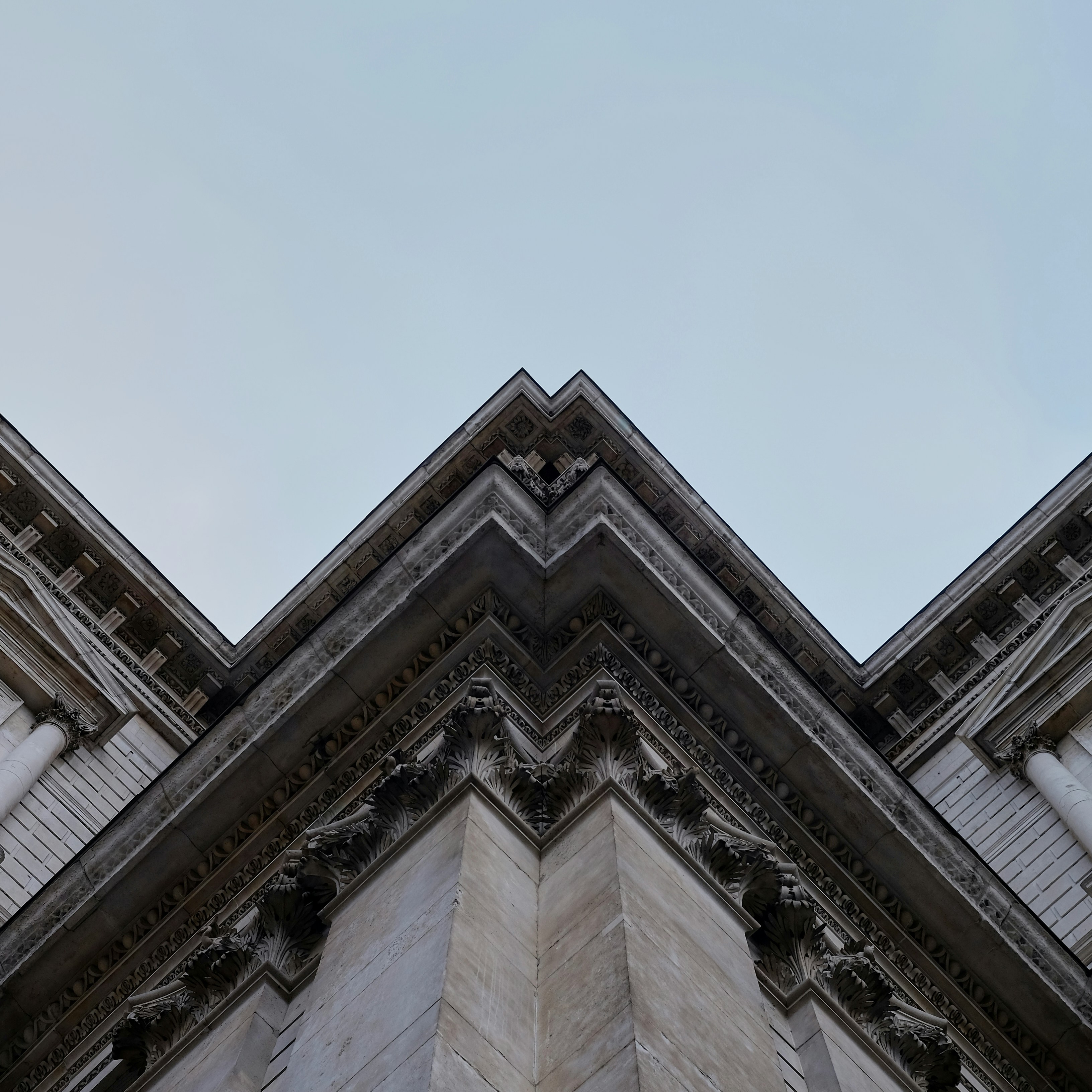 Stone Summit: A V-shaped Convergence of Ornate Cornices Under a Pale Sky