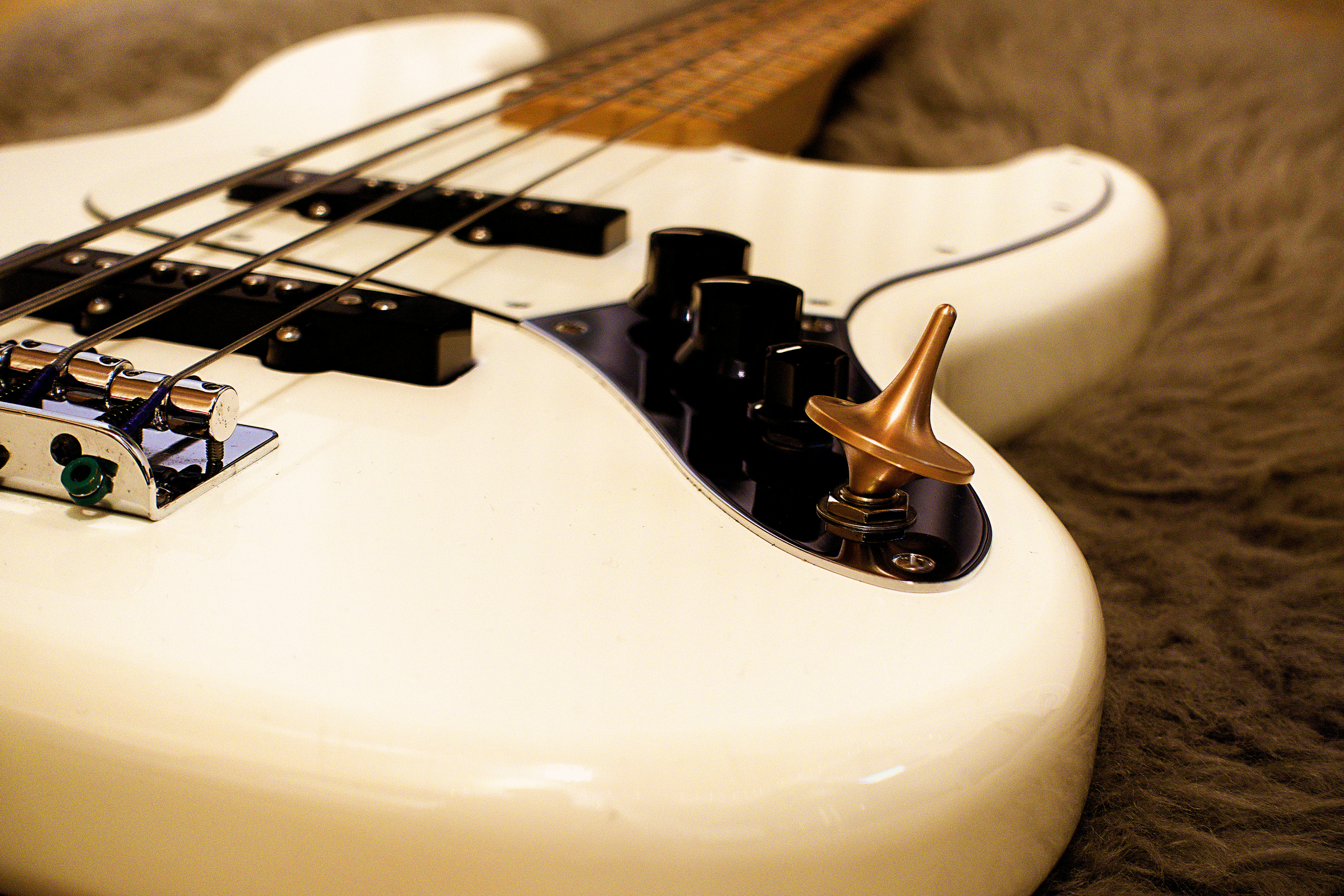 White bass guitar with gold hardware resting on plush fabric