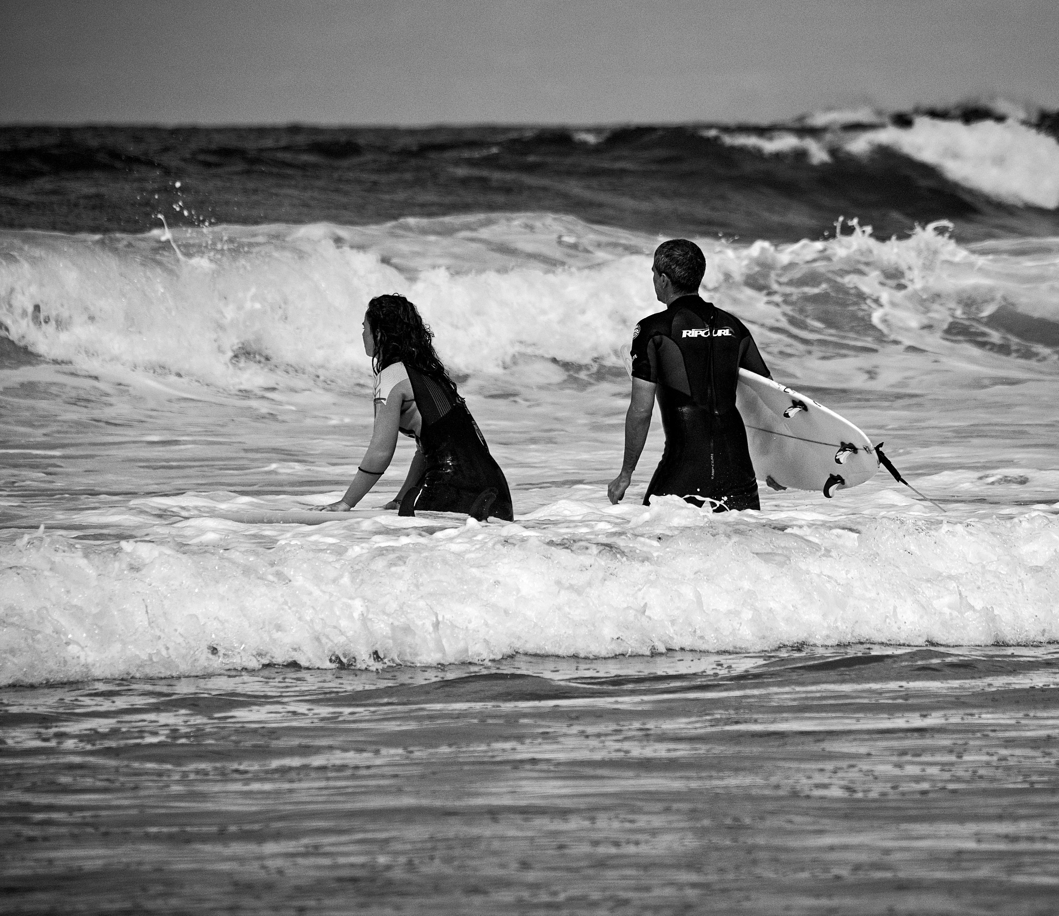 Surfing duo in crashing breakers: a black-and-white moment at the shoreline