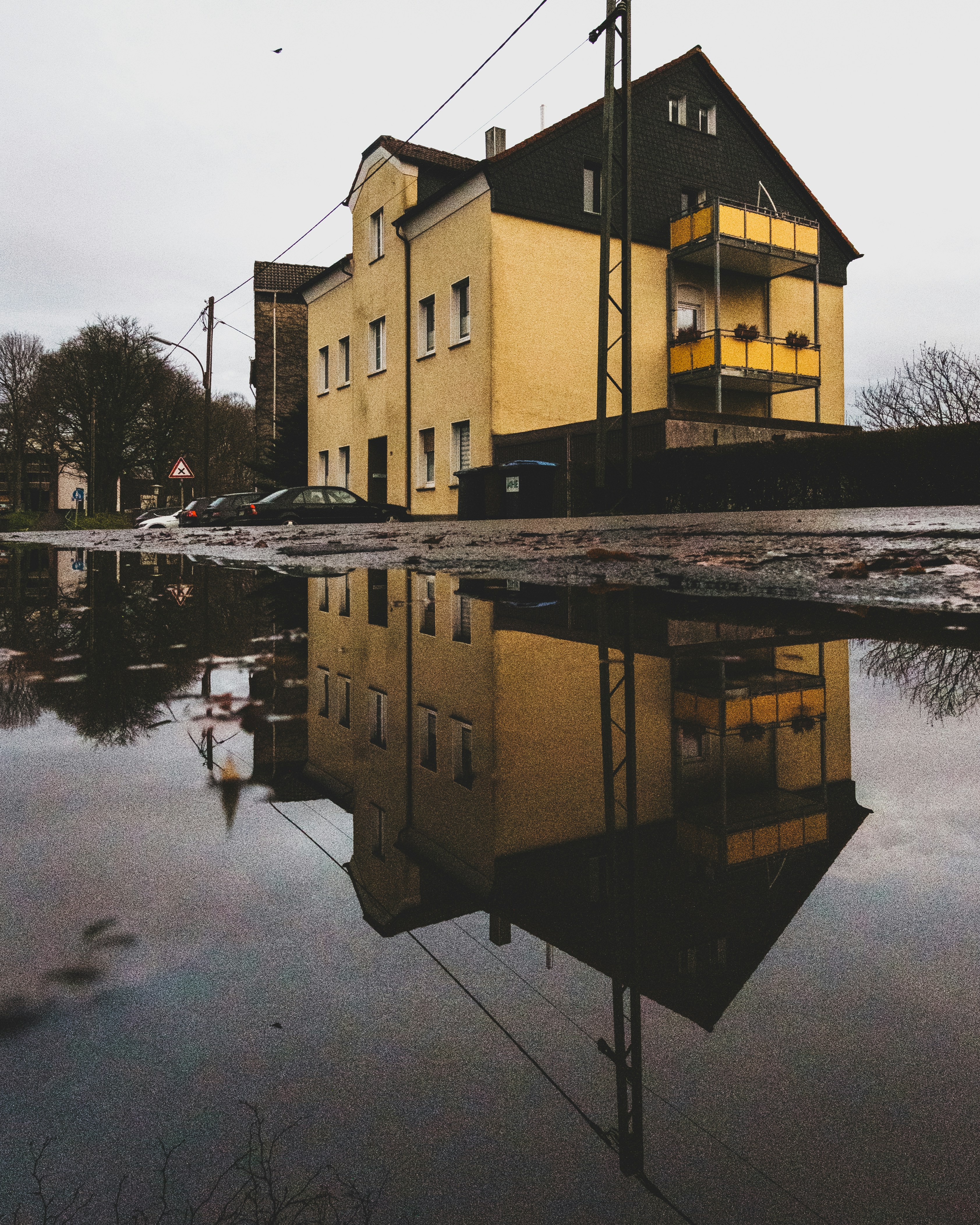 Yellow apartment building mirrored in a rain-soaked street