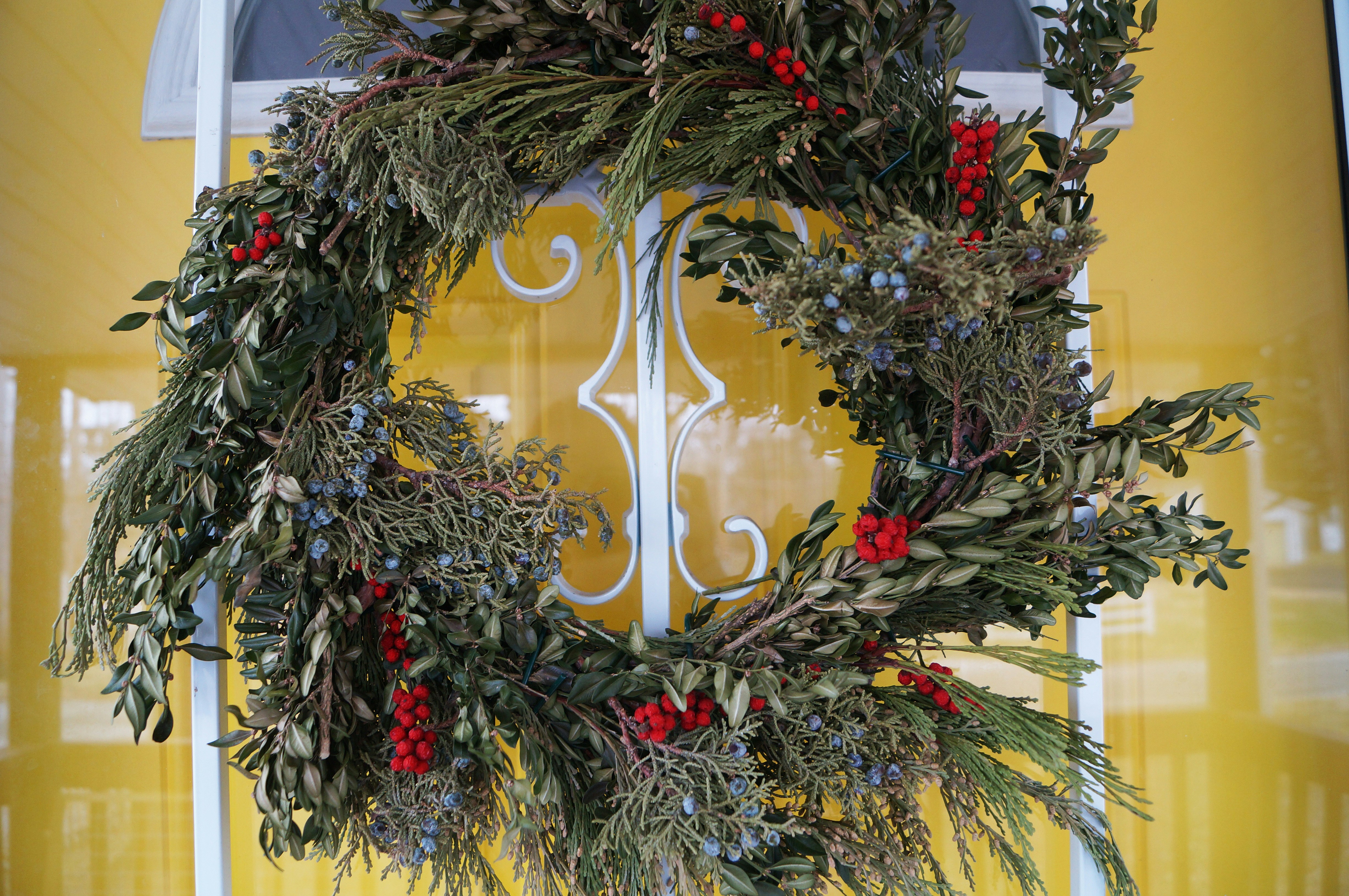 Evergreen Wreath Framing a Sunlit Yellow Storefront