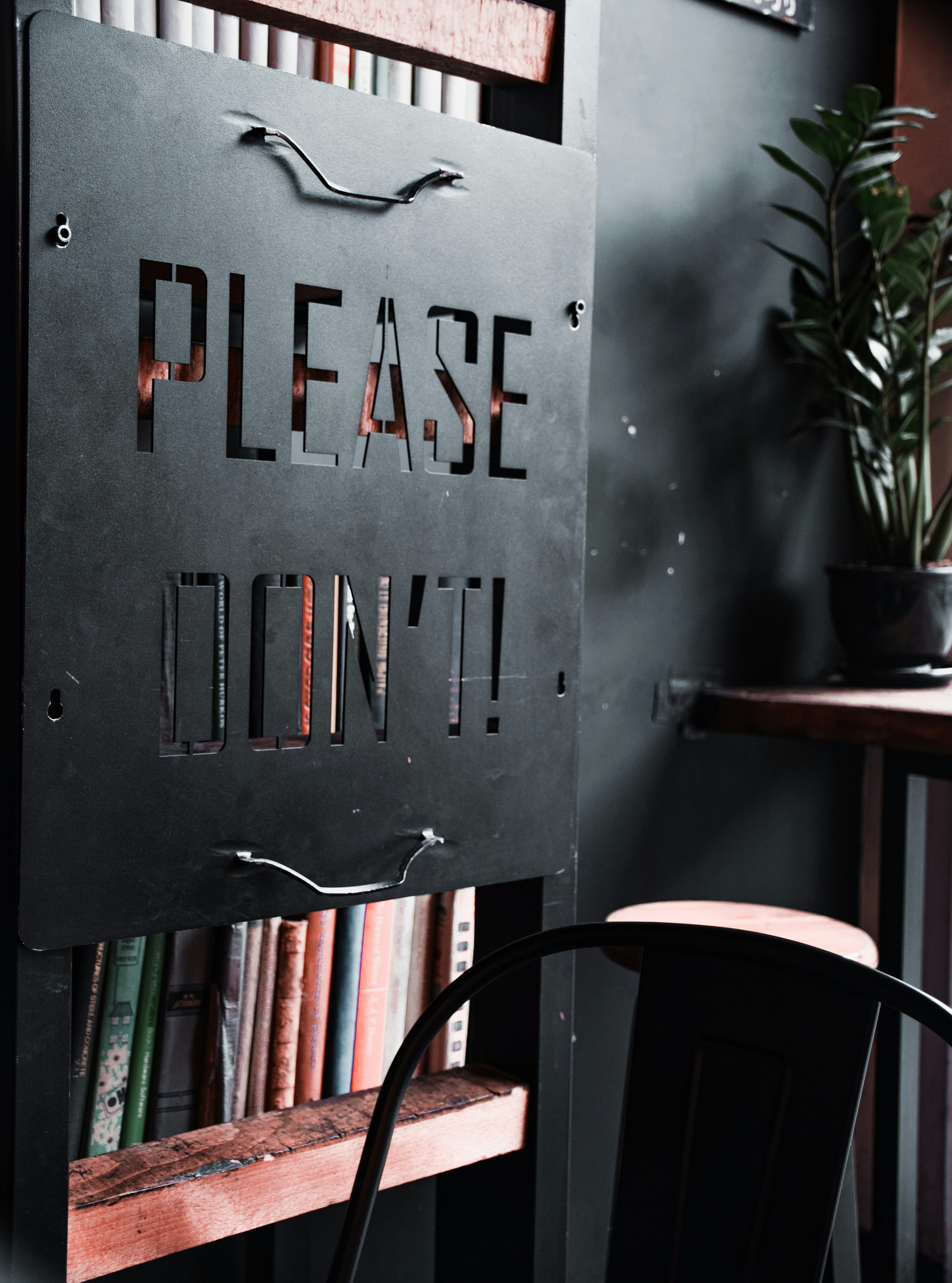 Please Don’t! A Metal Sign Over Library Shelves in a Cozy Cafe