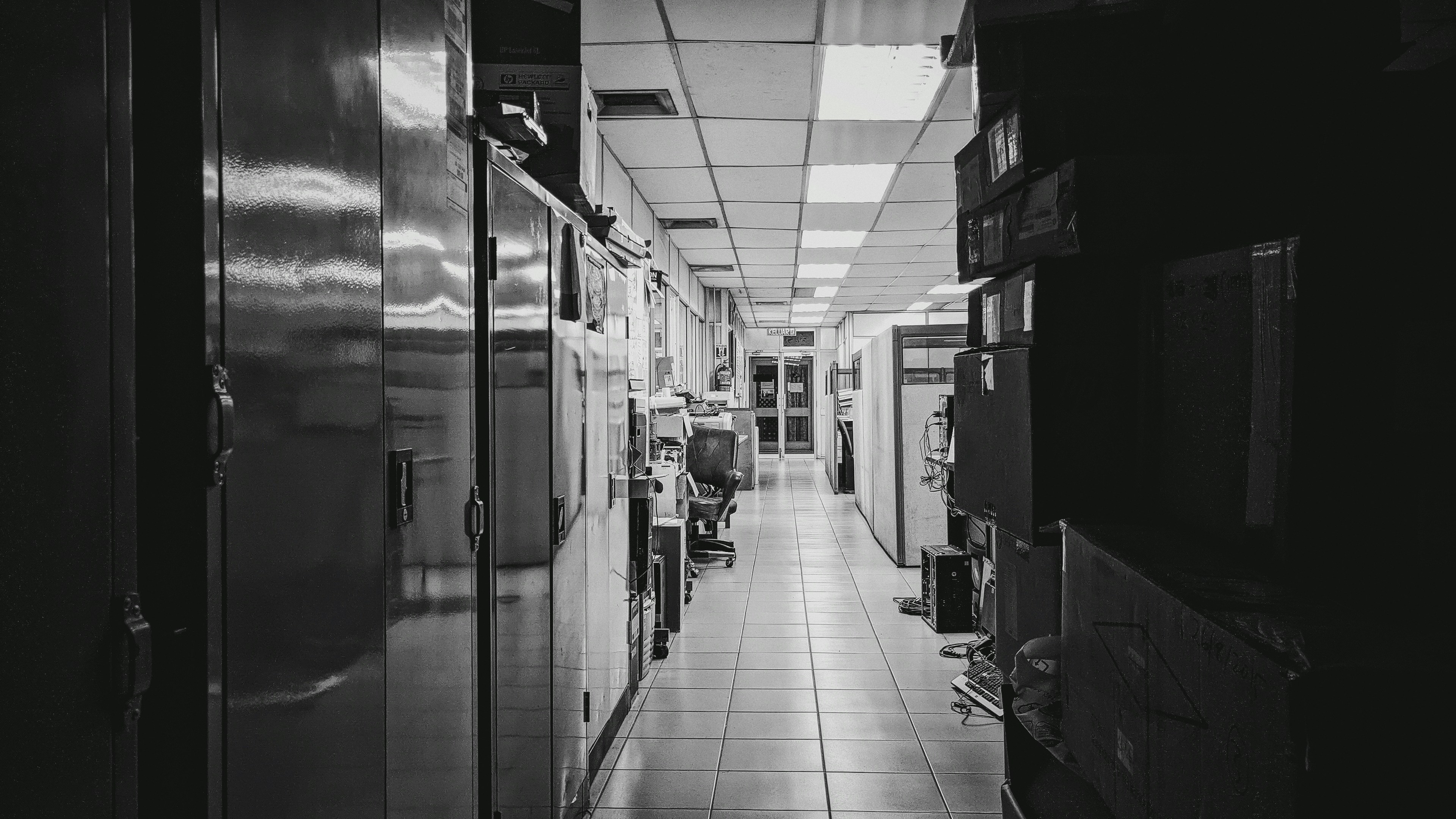 Grayscale train station corridor with symmetrical lighting and reflective surfaces.