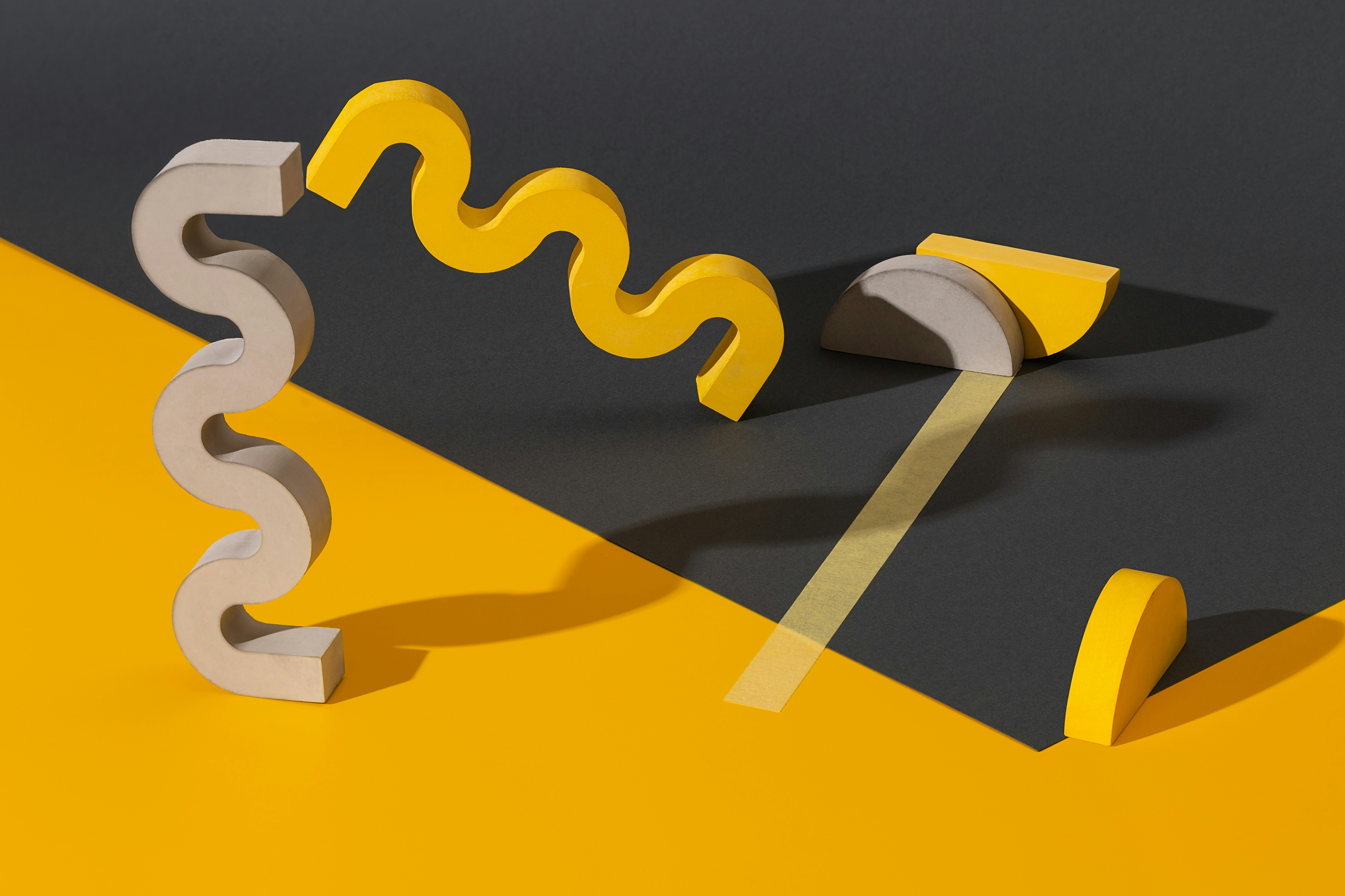 Abstract arrangement of geometric shapes in yellow and gray, highlighting curves and angles. The interplay of colors and forms creates a dynamic visual experience.