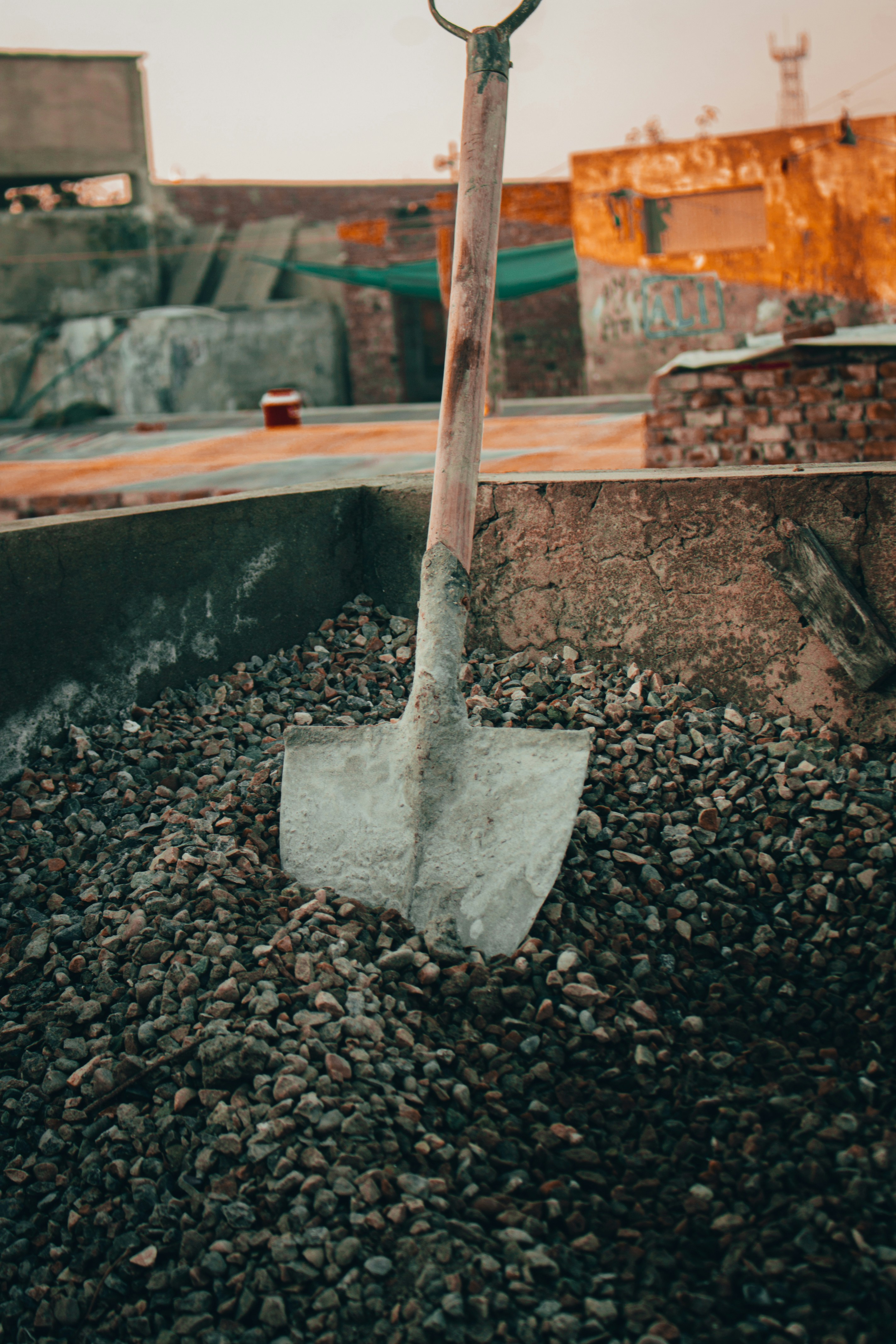 Rusted Urban Shovel Standing Over Pebbled Bed in a Rooftop Scene