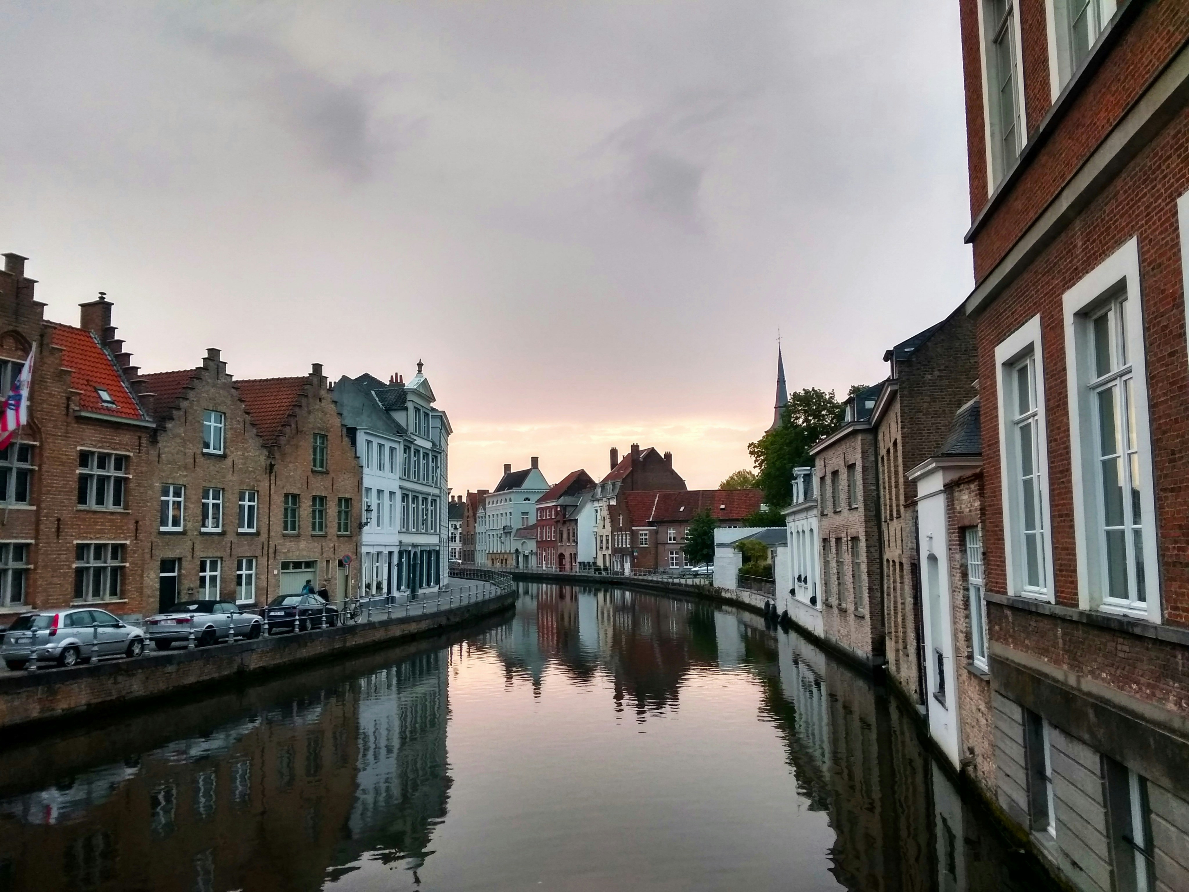 Charming canal scene in Bruges, showcasing historic buildings mirrored in the water during twilight.