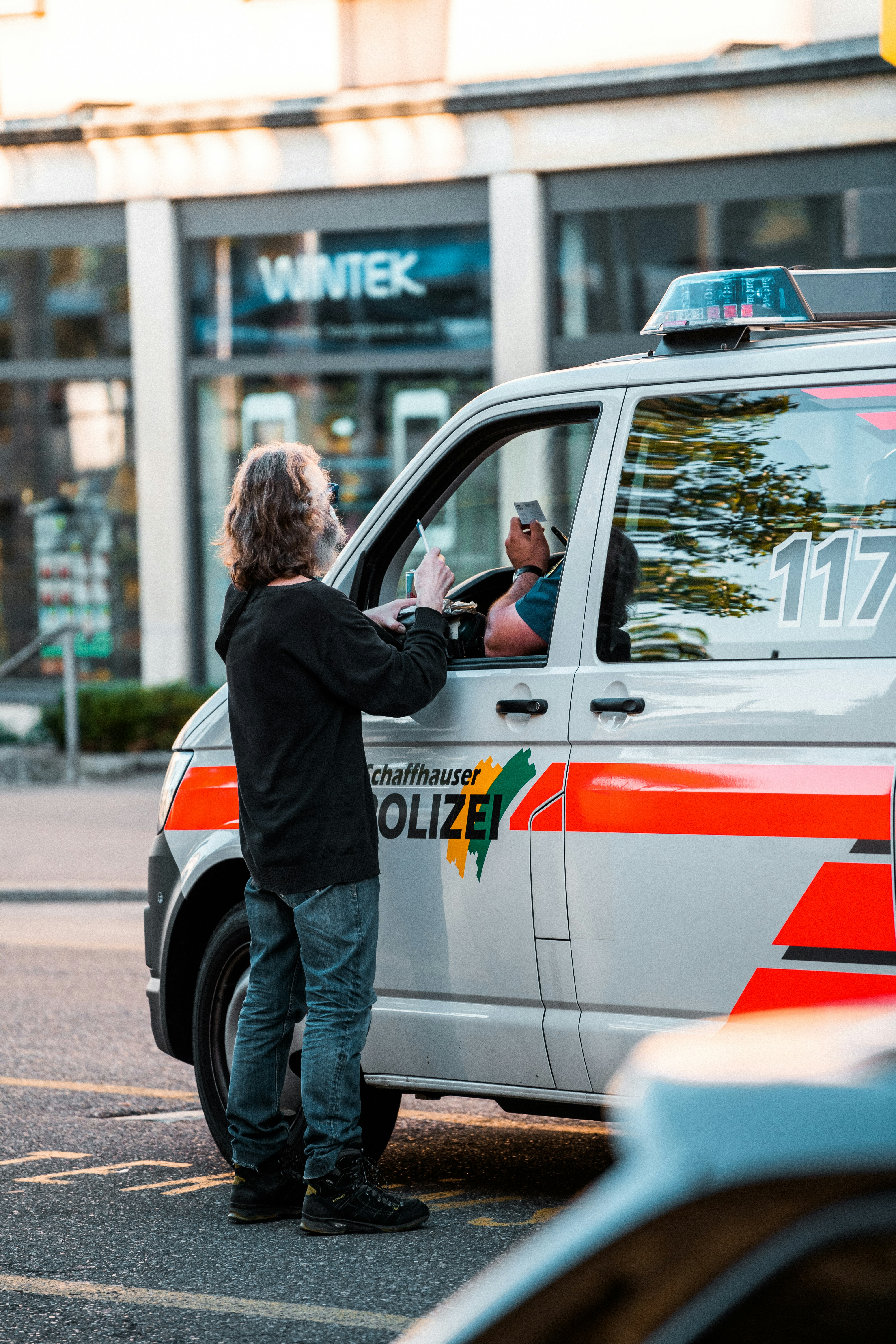 Hands Raised, Police Van in Focus: A Street Exchange