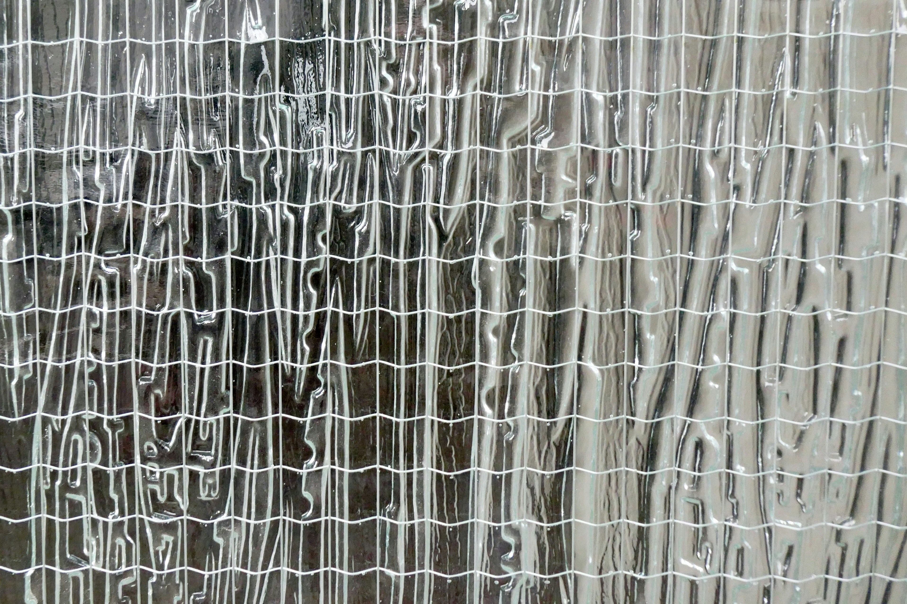 Intricate pattern of a textured plastic sheet with a grid design, reflecting subtle colors and shapes behind it.