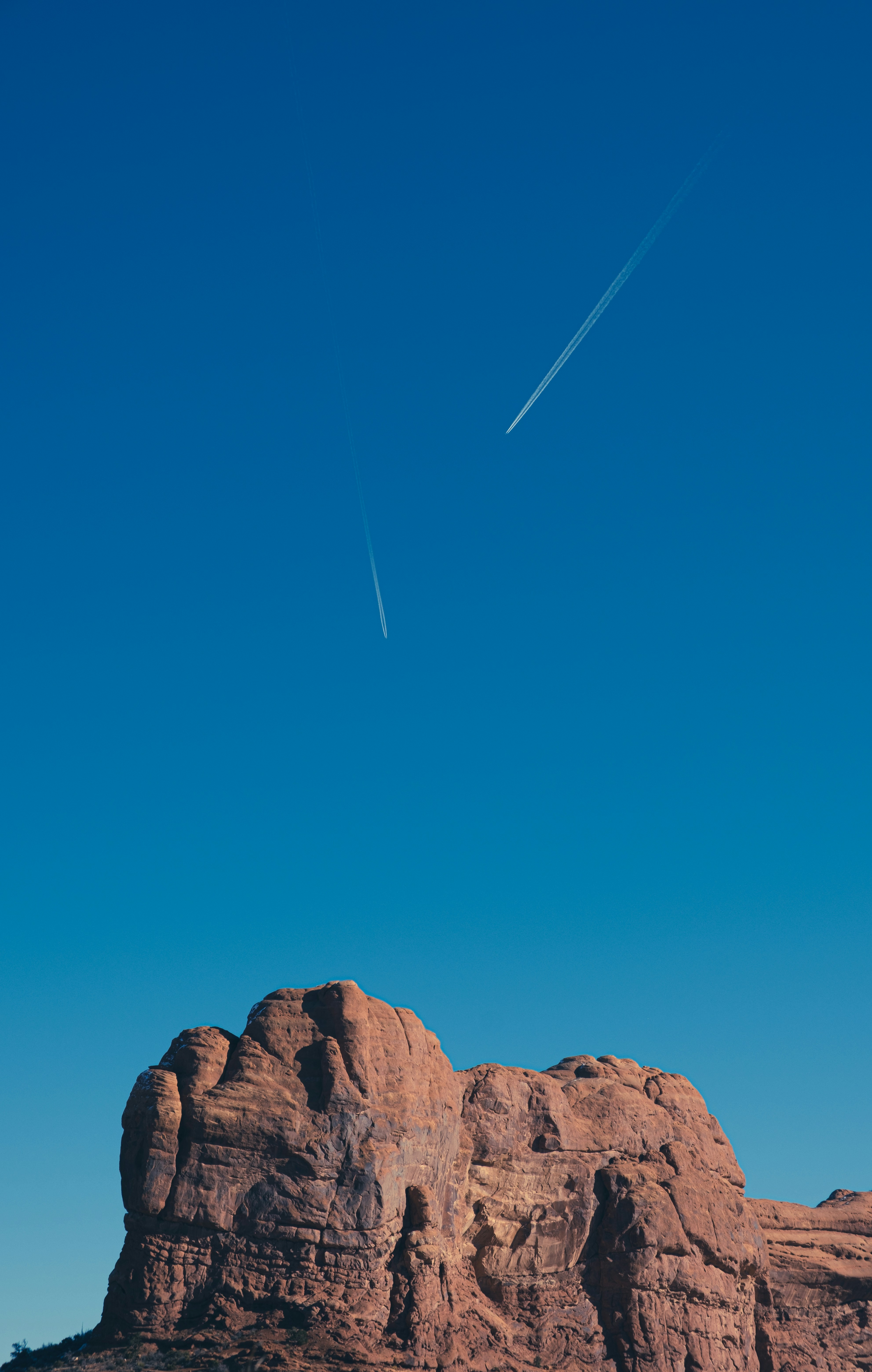 Twin Contrails Over a Weathered Desert Sentinel