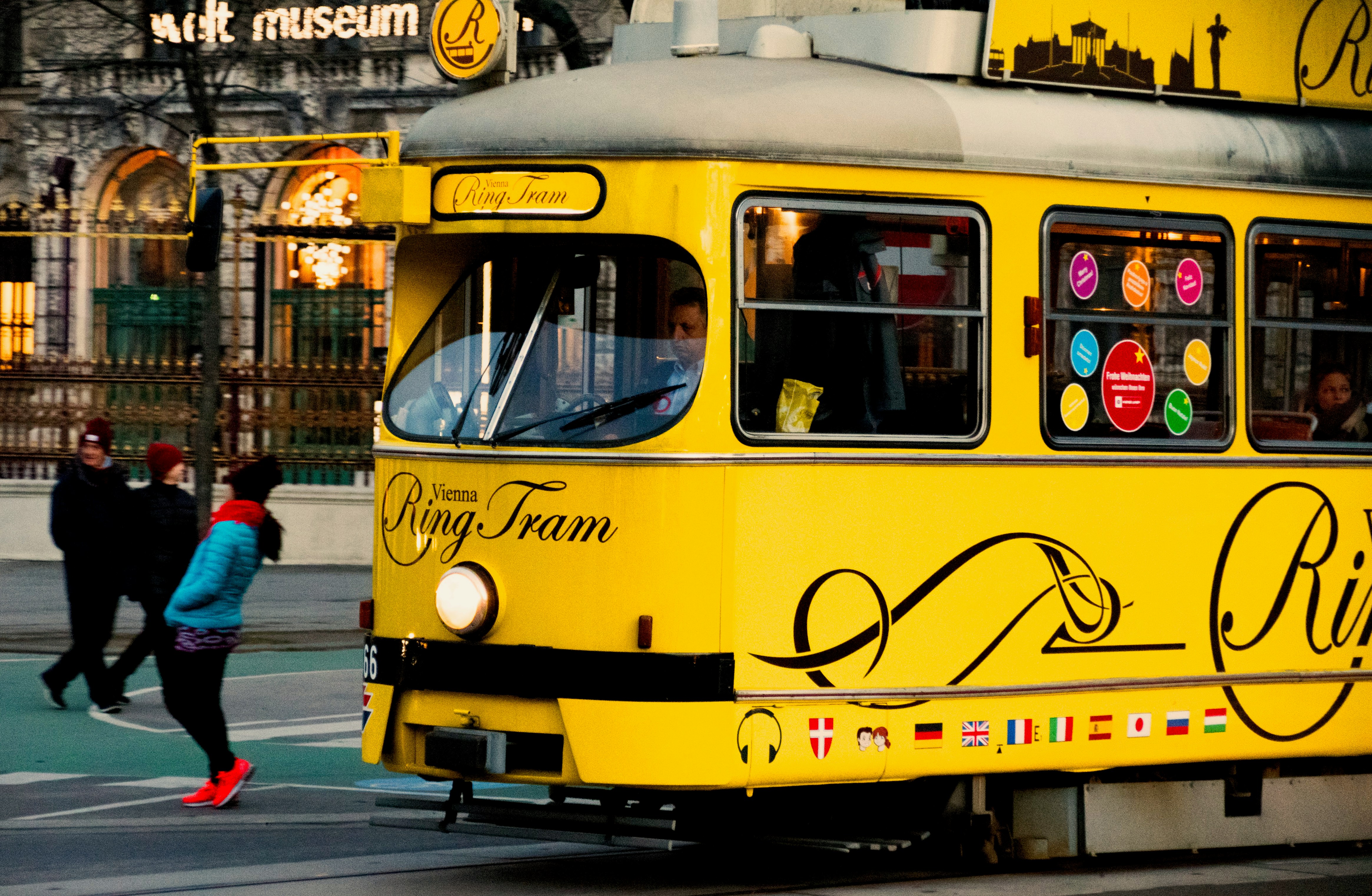 Yellow Ring Tram navigating the streets of Vienna, with pedestrians in the foreground and historical architecture in the background.