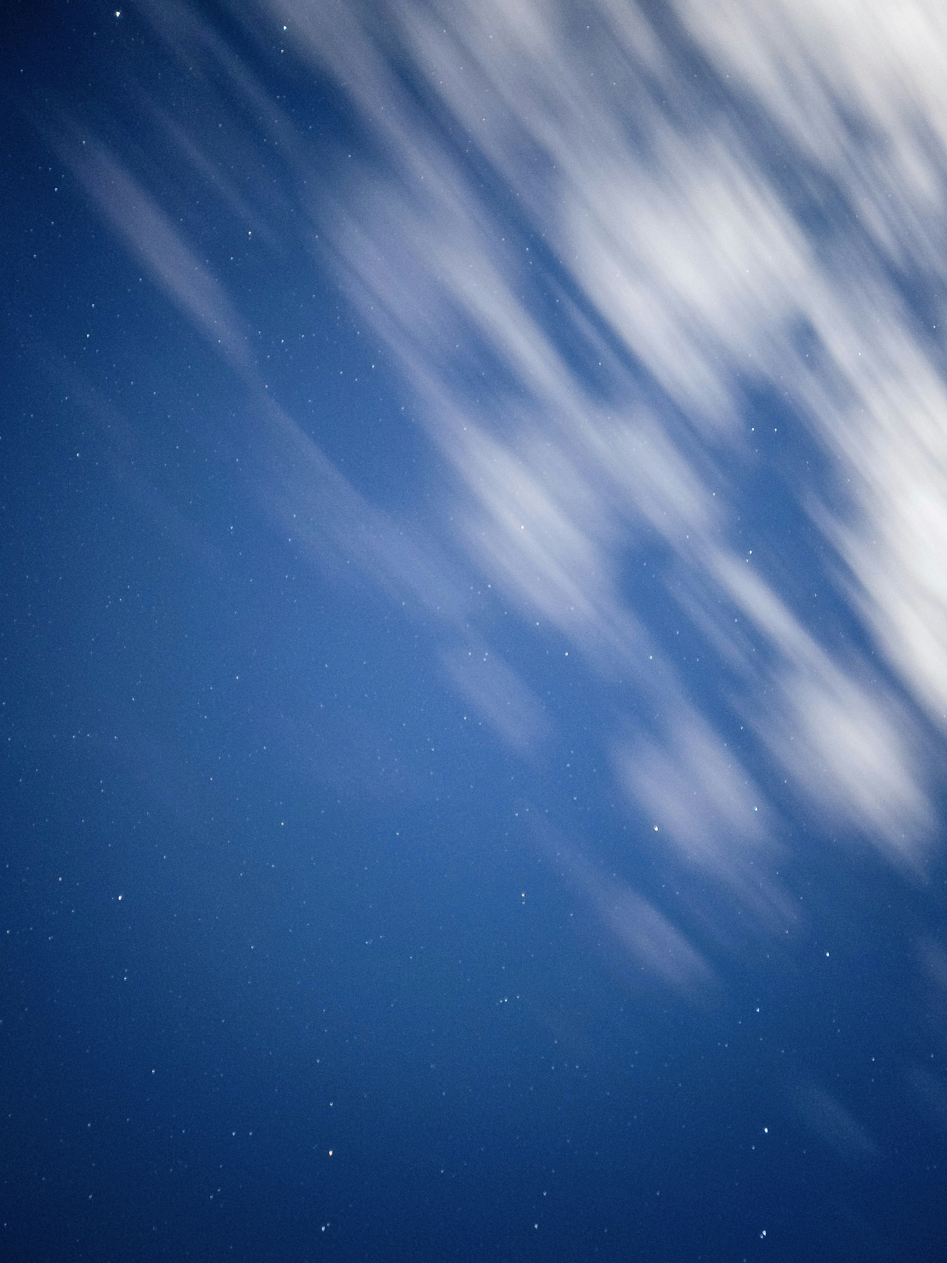 Trailing Clouds Over a Starry Night Sky